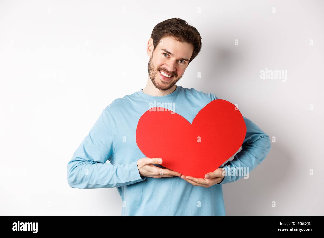 Charming lover man holding Valentines day red heart and smiling, I love ...