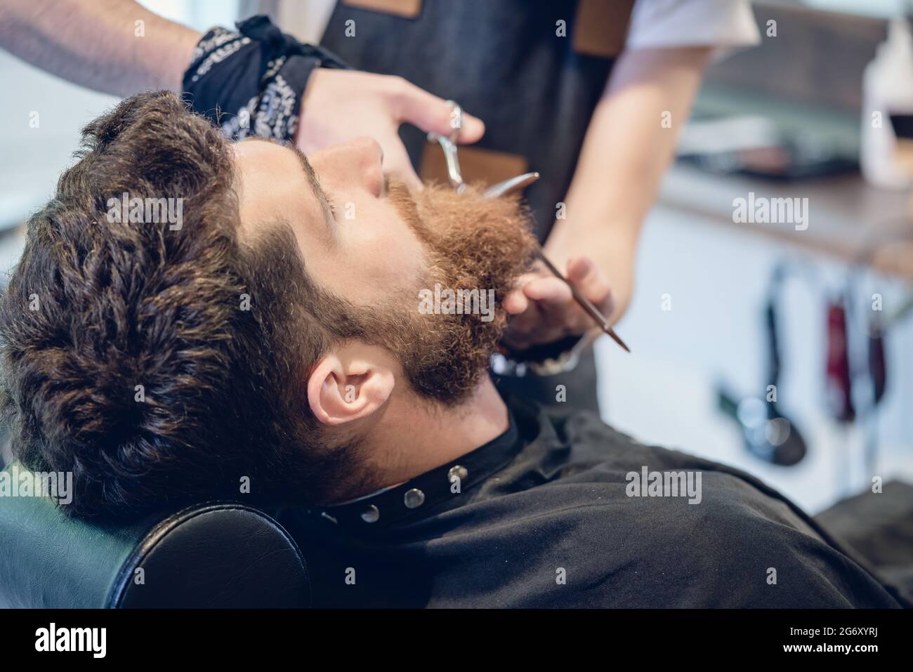 Close-up of the hand of a skilled barber using scissors, while trimming ...