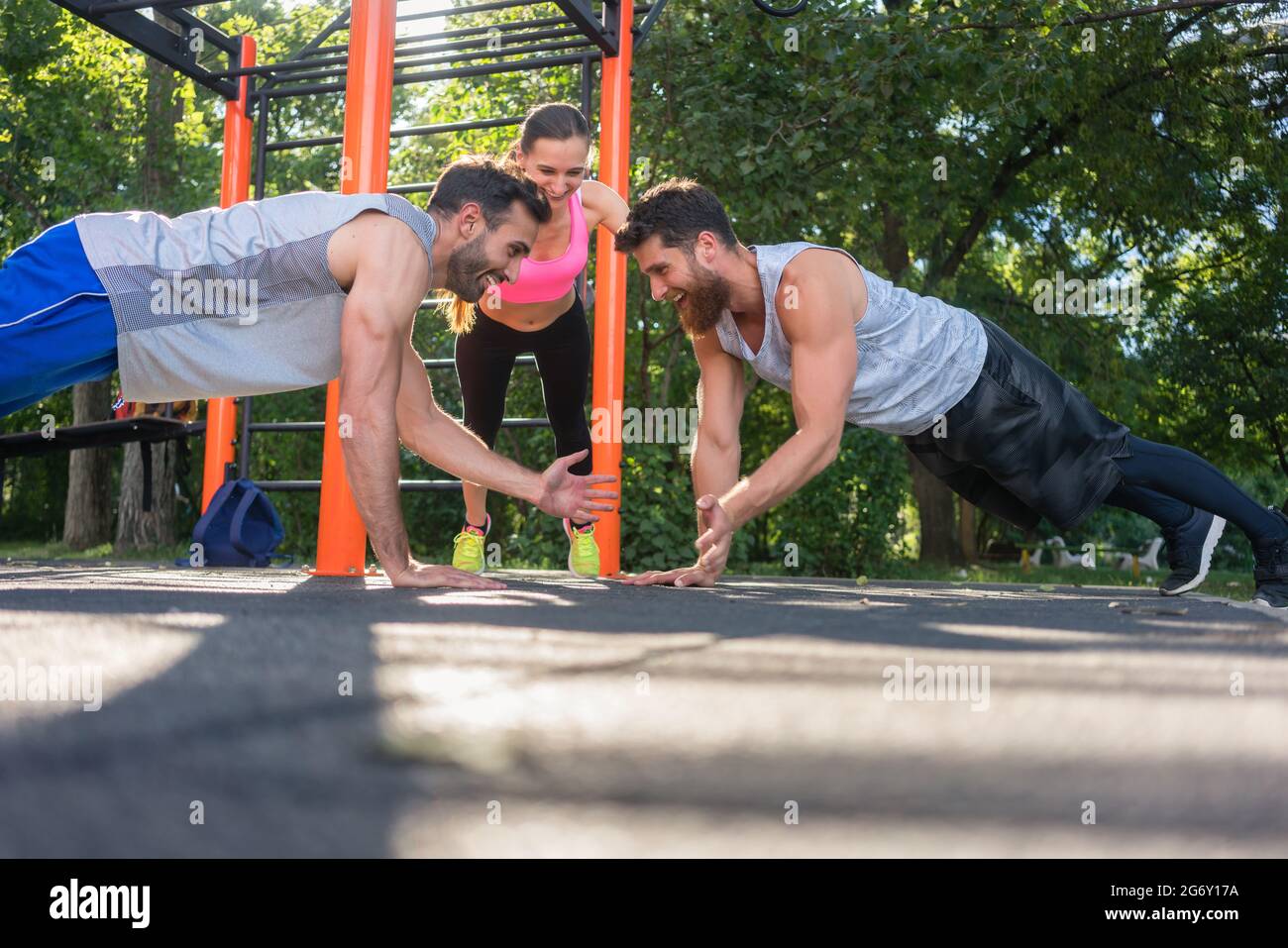 Two fit young men clapping hands from face to face plank position ...