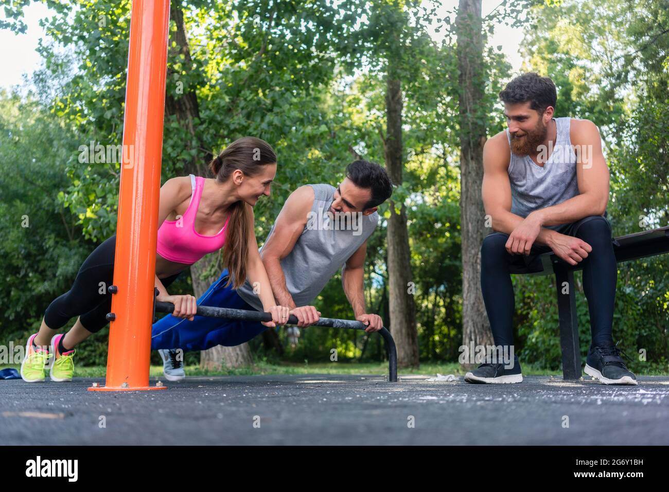Low-angle view of a young determined couple in love doing push-ups ...