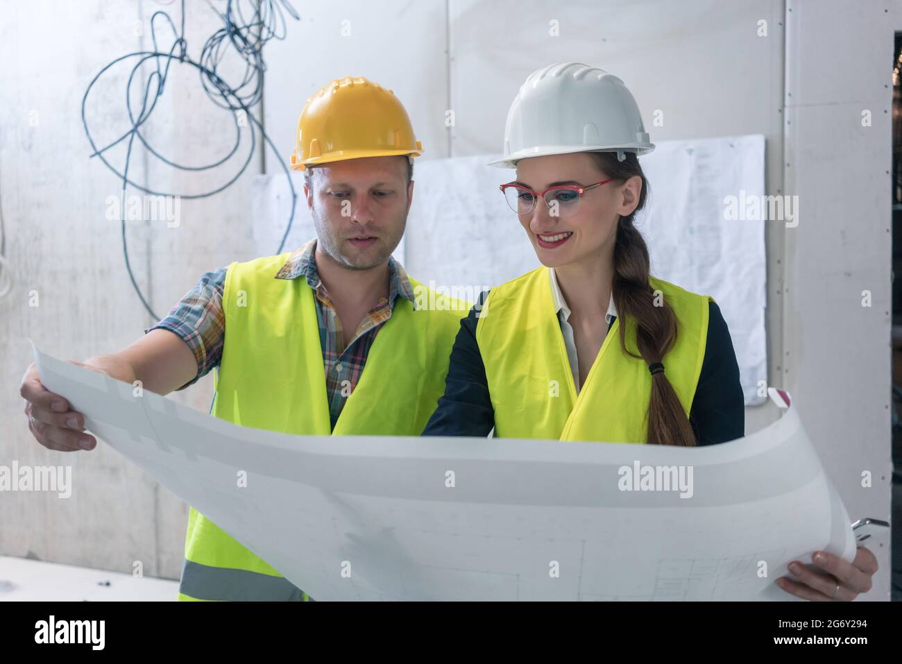 Construction worker and architect reading plan on site Stock Photo - Alamy