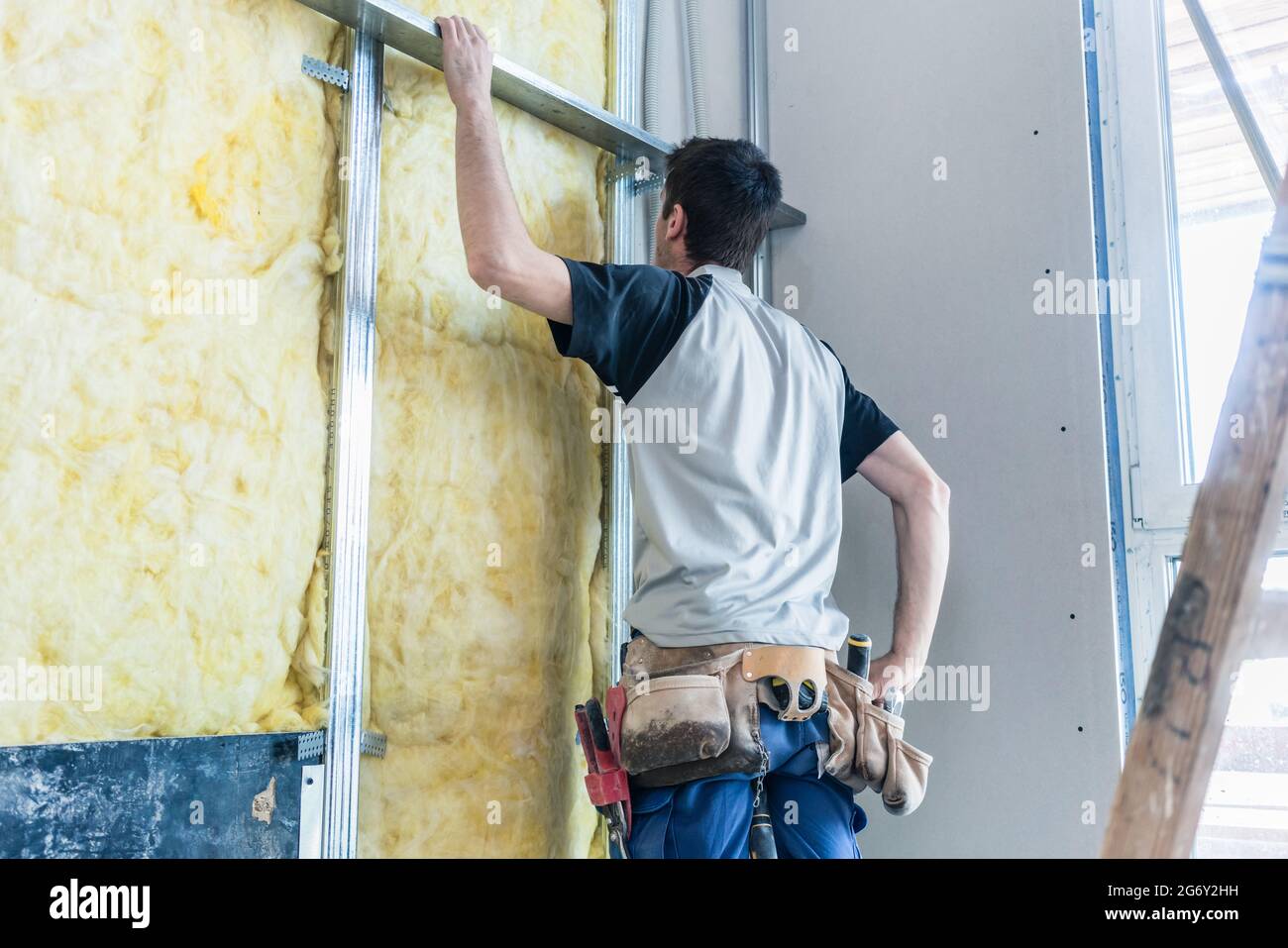 Worker putting insulation on wall of a new building on construction ...