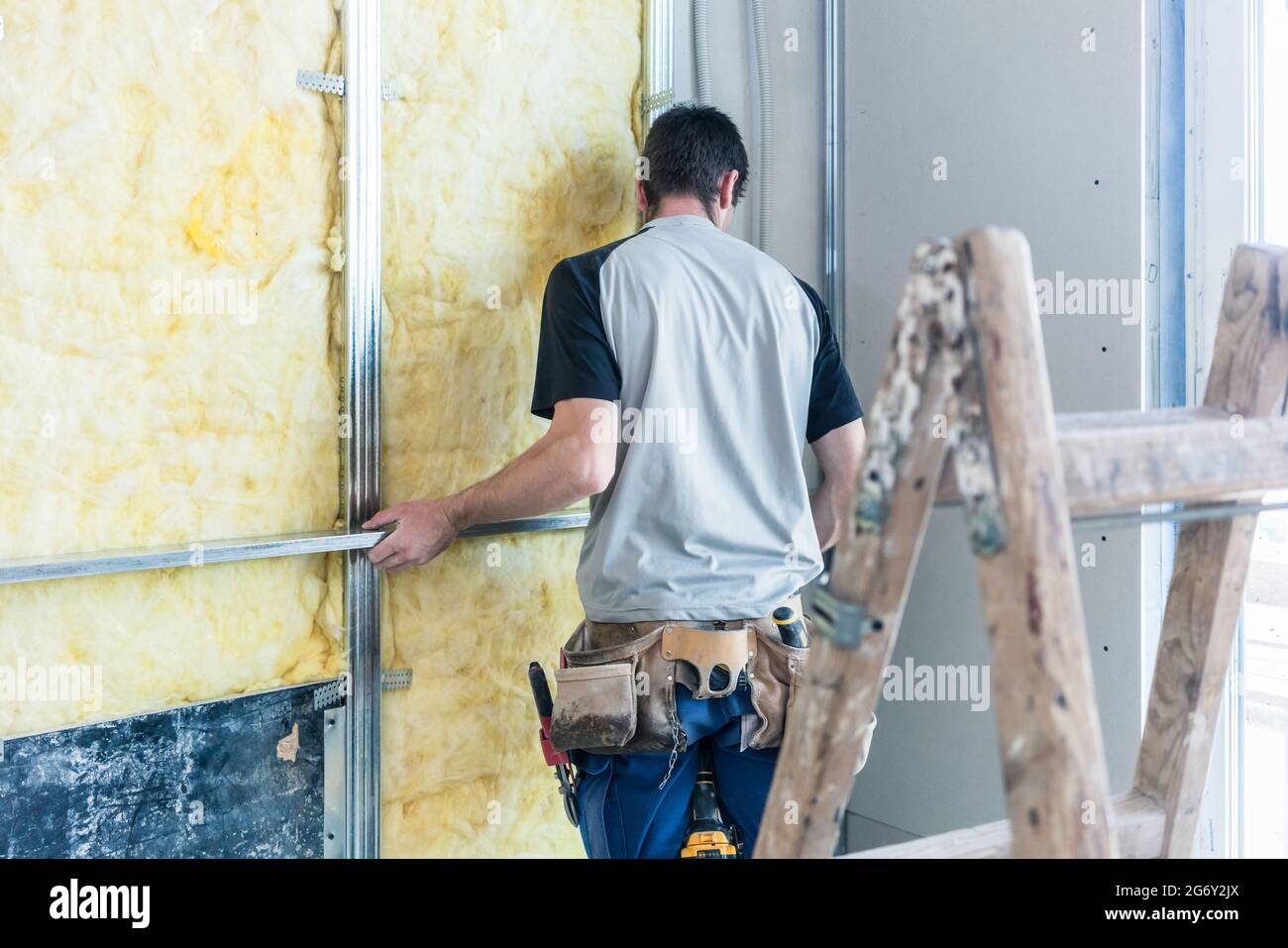 Worker putting insulation on wall of a new building on construction ...