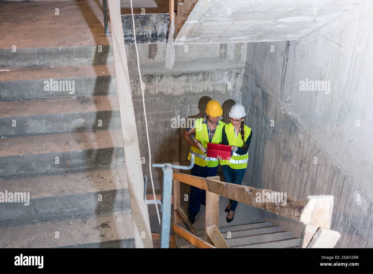 Construction worker and builder inspecting stairs in a building shell ...