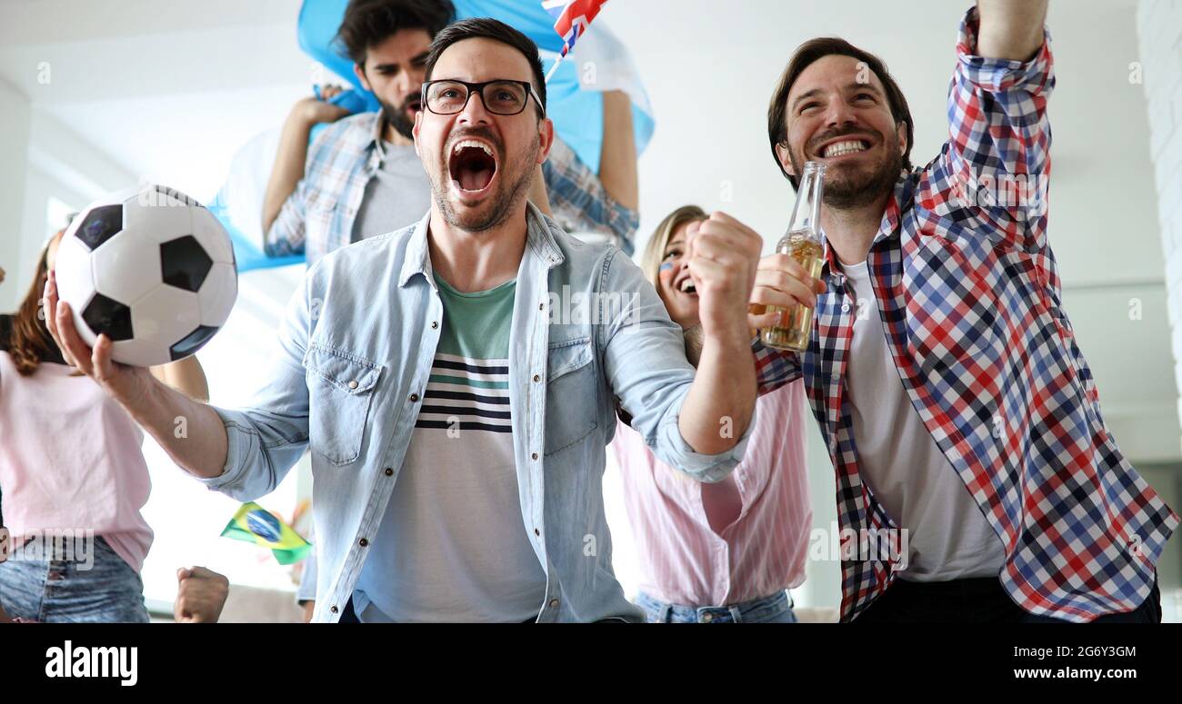 Happy group of young friends watching television and supporting their ...
