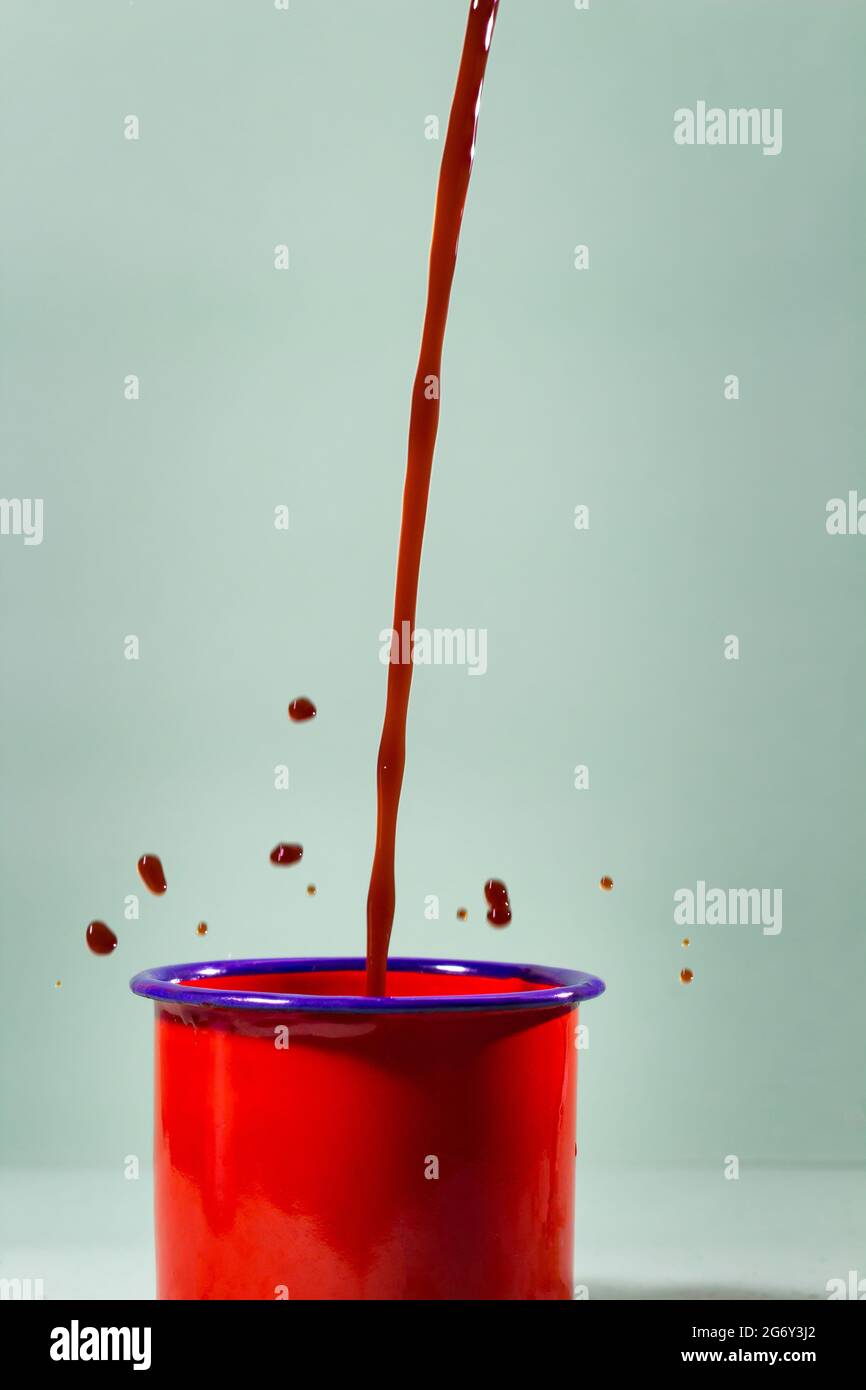 Pouring coffee in the red mug with green background Stock Photo - Alamy