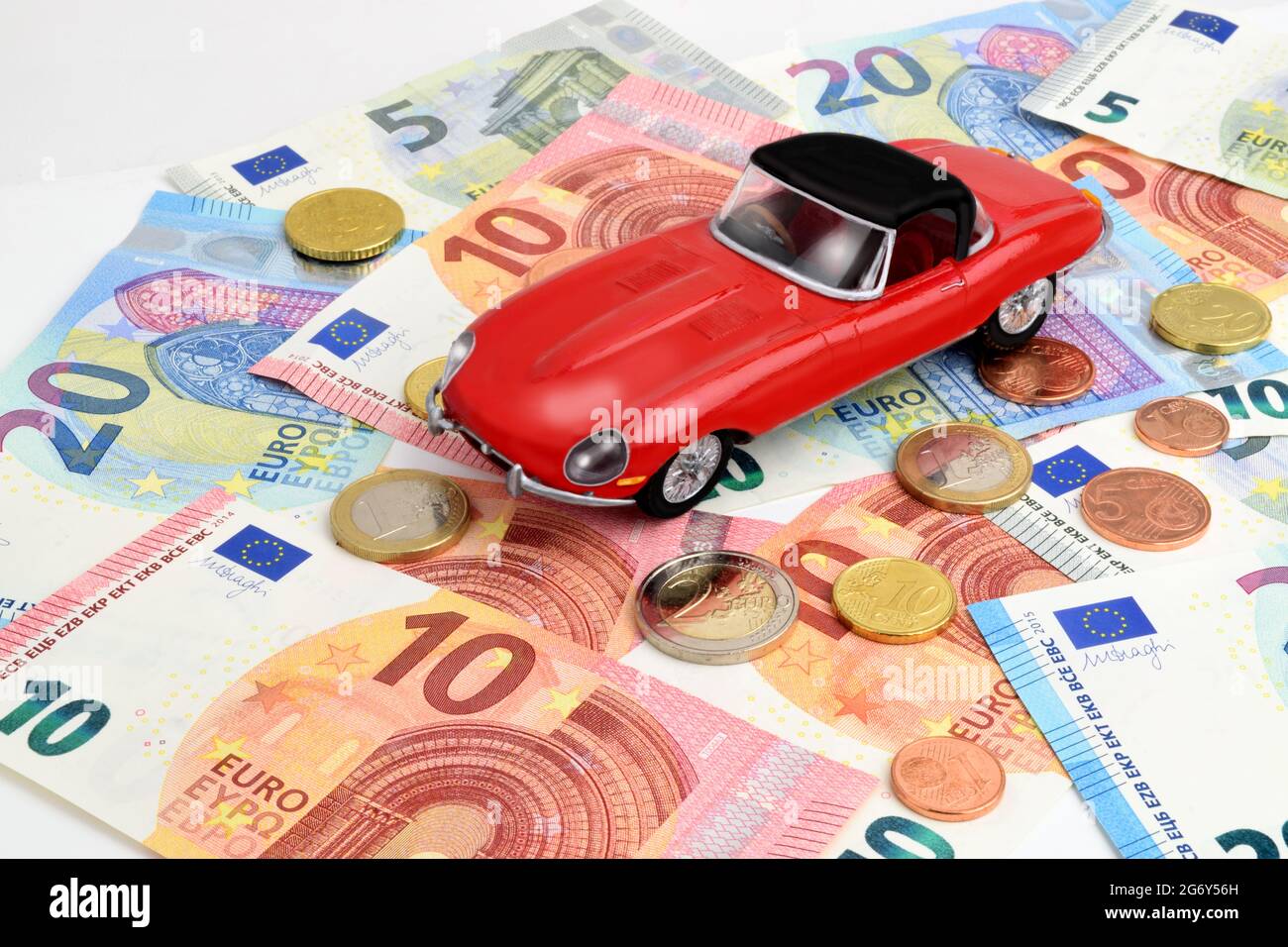 A red classic car on Euro notes and coins to represent Euro car finance ...