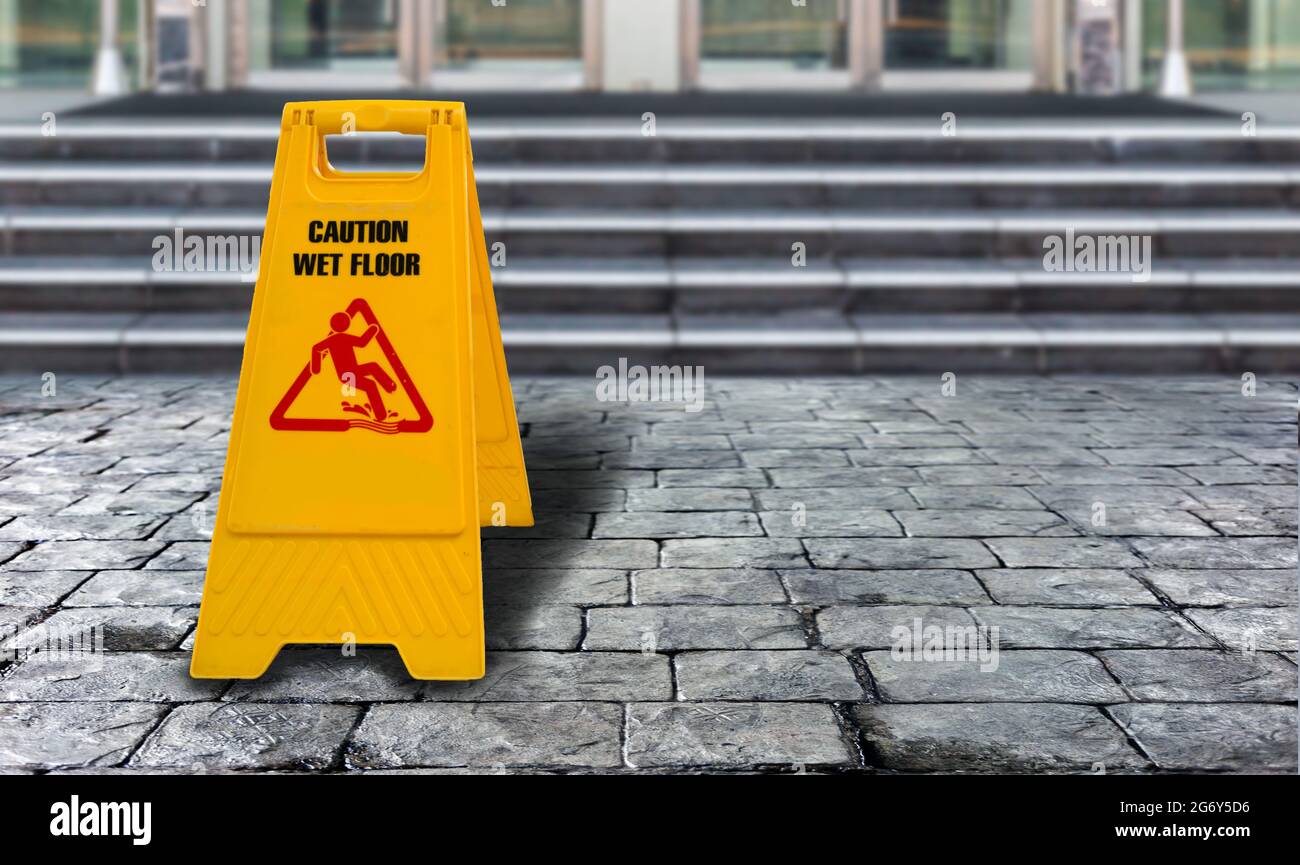 warning sign caution wet floor on street front of building in raining ...
