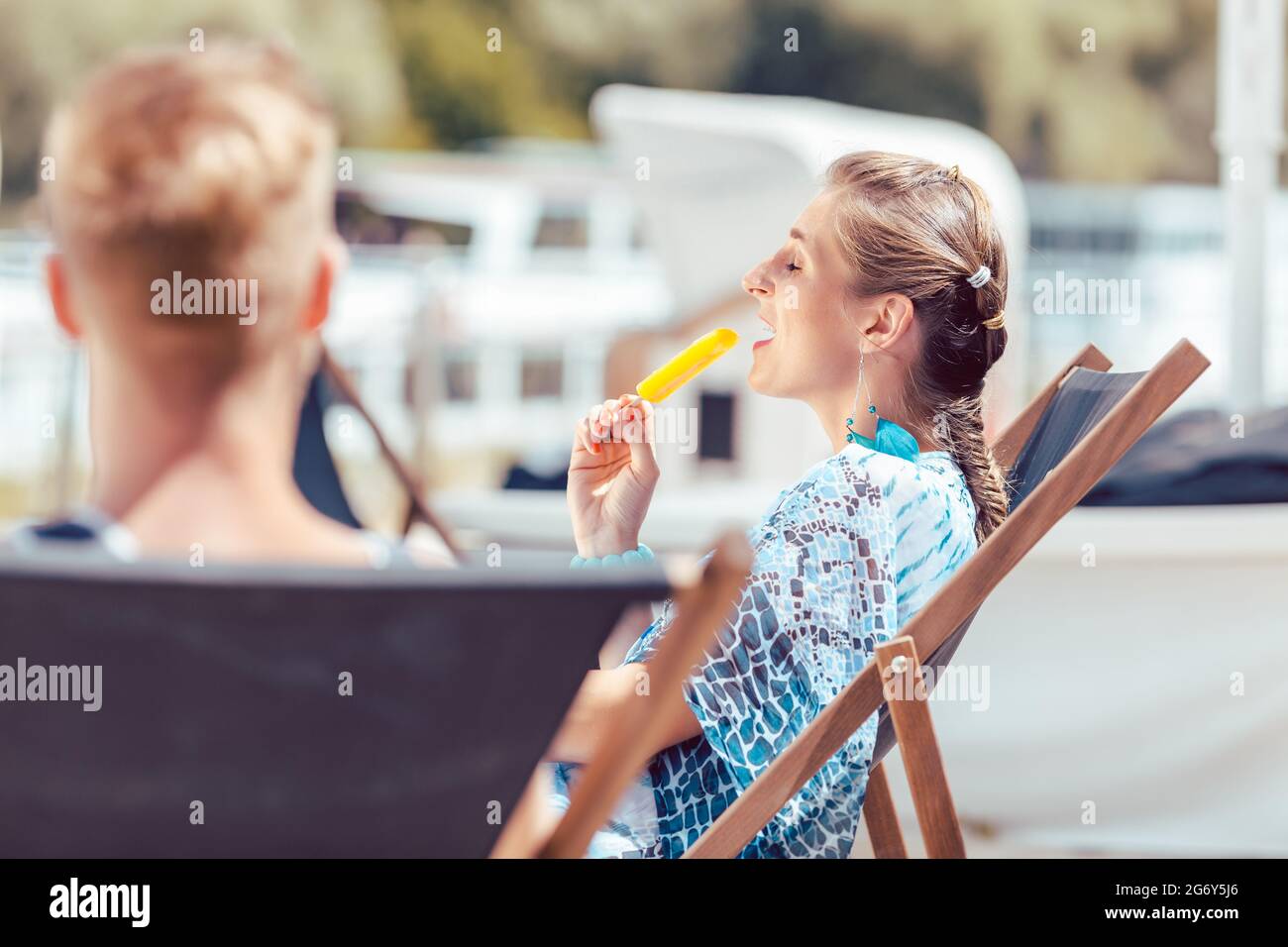 Young woman sitting on chair eating popsicle Stock Photo - Alamy