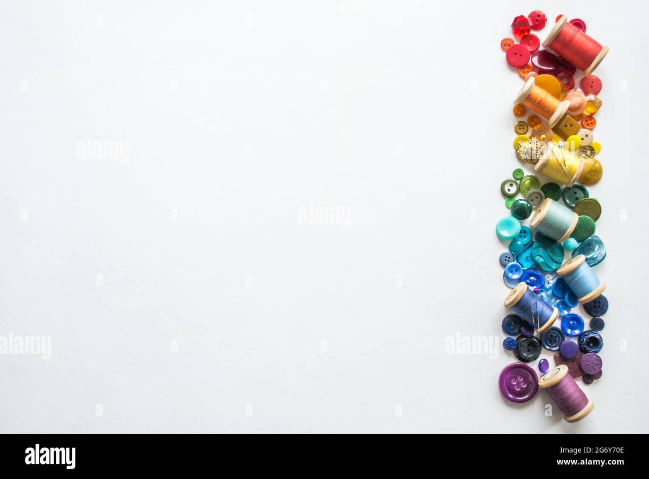 A lot of buttons and reels with colorful threads, laid out on a white ...