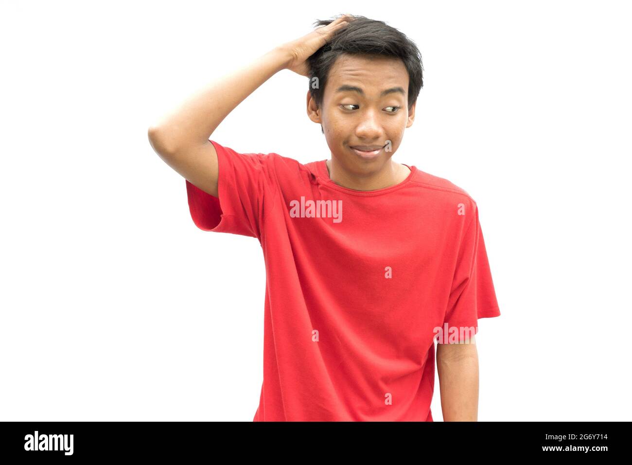 Young Indonesian guy fixing his hair with a nimble face on a white wall ...