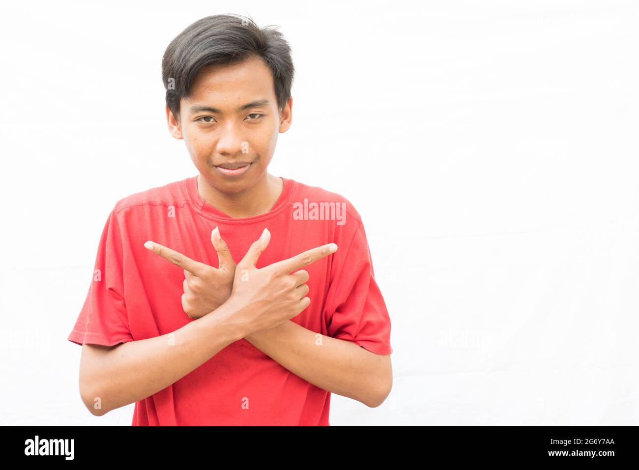 Young Asian guy posing with hands crossed and finger guns Stock Photo ...