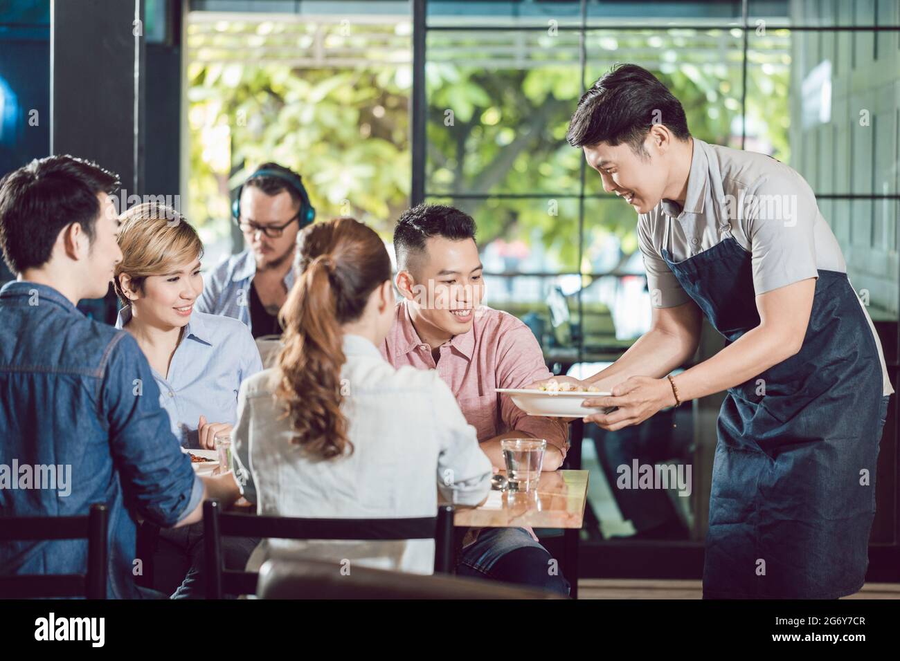 Happy male waiter serving food to the customers in the restaurant Stock ...