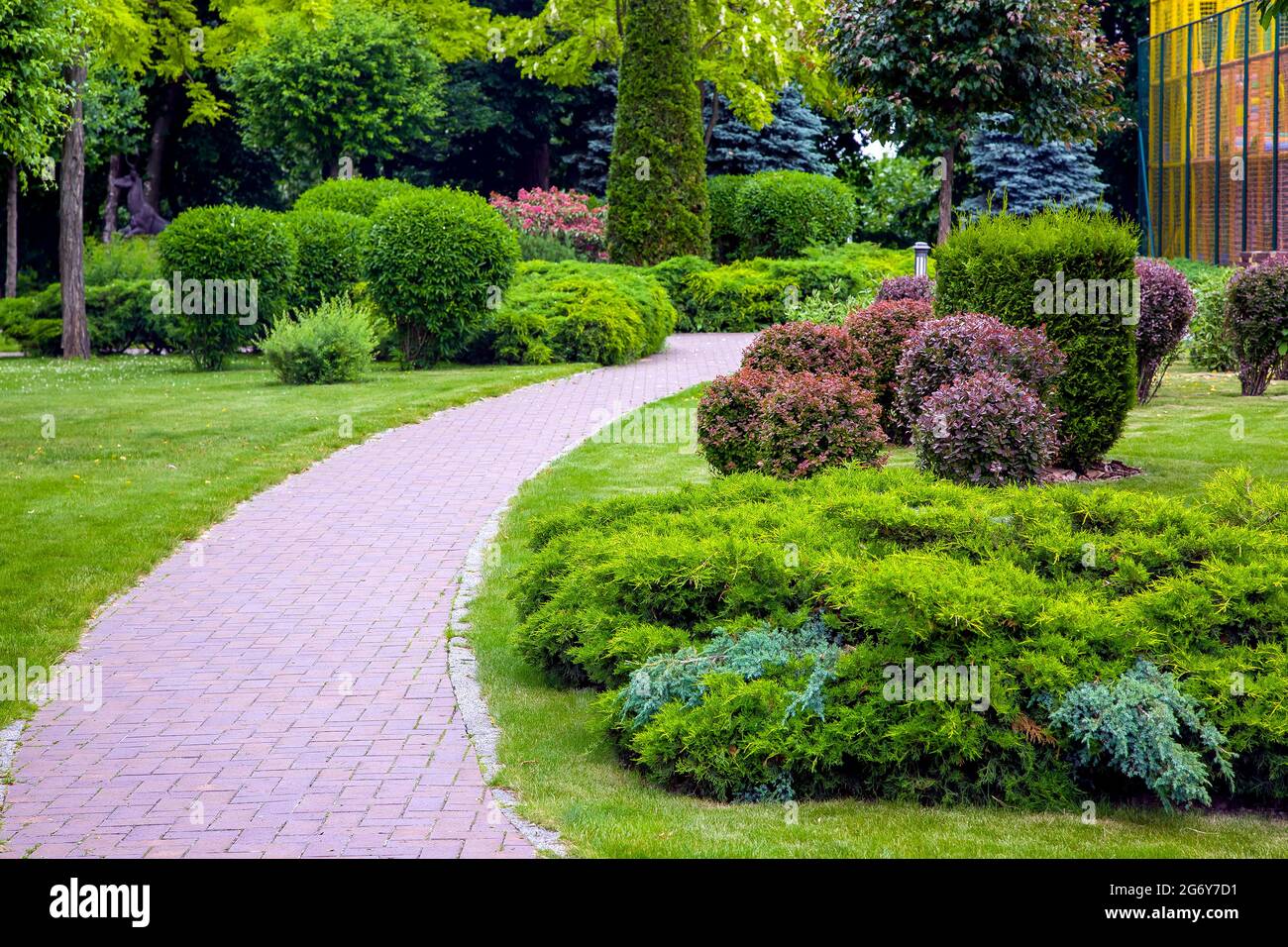 pedestrian pavement of stone tiles in park with landscaping and green ...