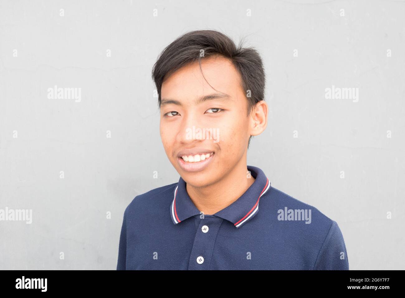 Young Indonesian guy smiling on a white wall background Stock Photo - Alamy