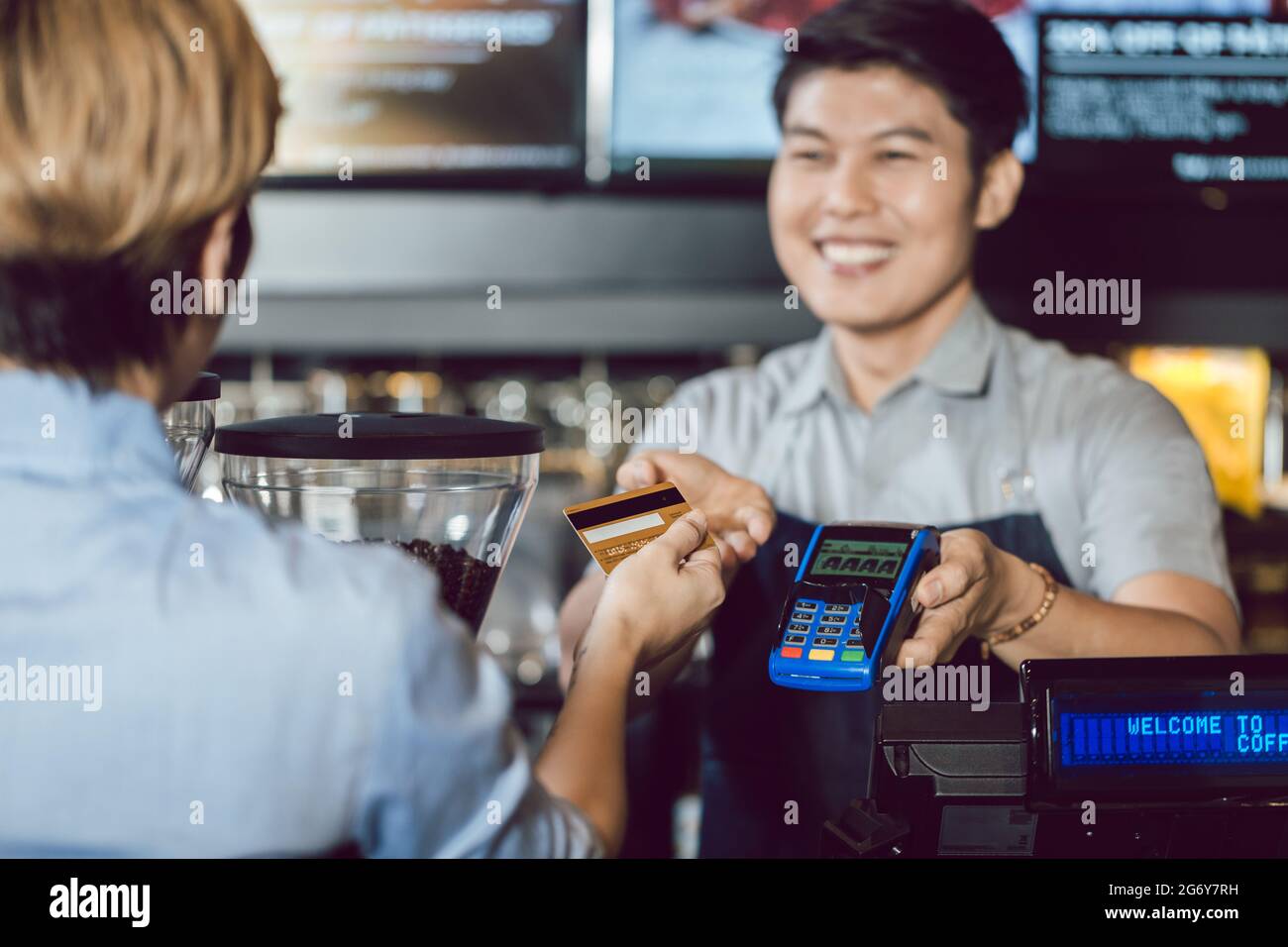Smiling male barista giving payment service for customer with credit ...