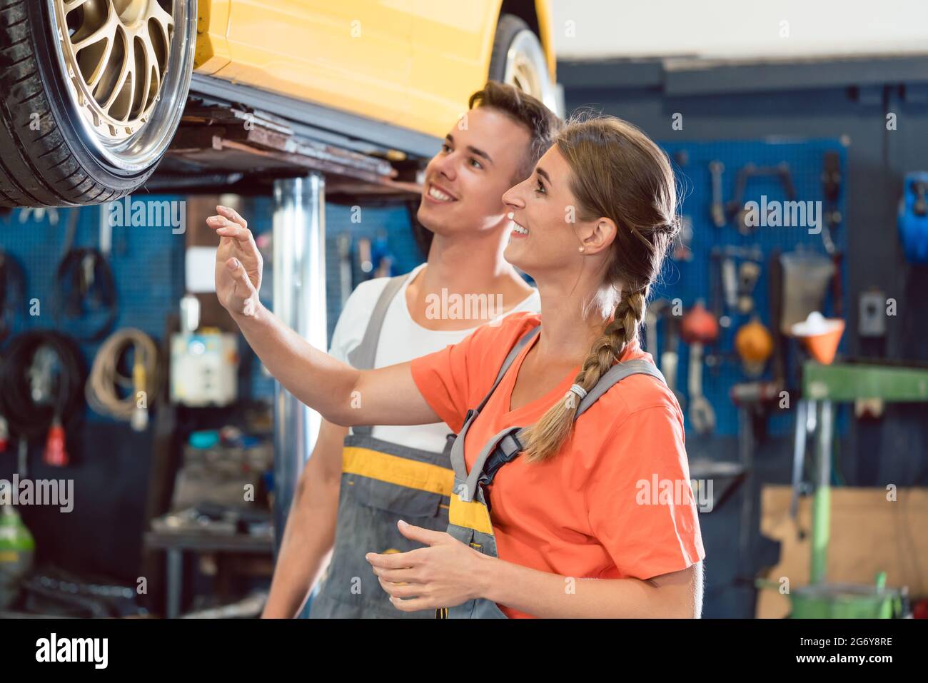 Two happy dedicated auto mechanics, checking the modified wheels of a ...