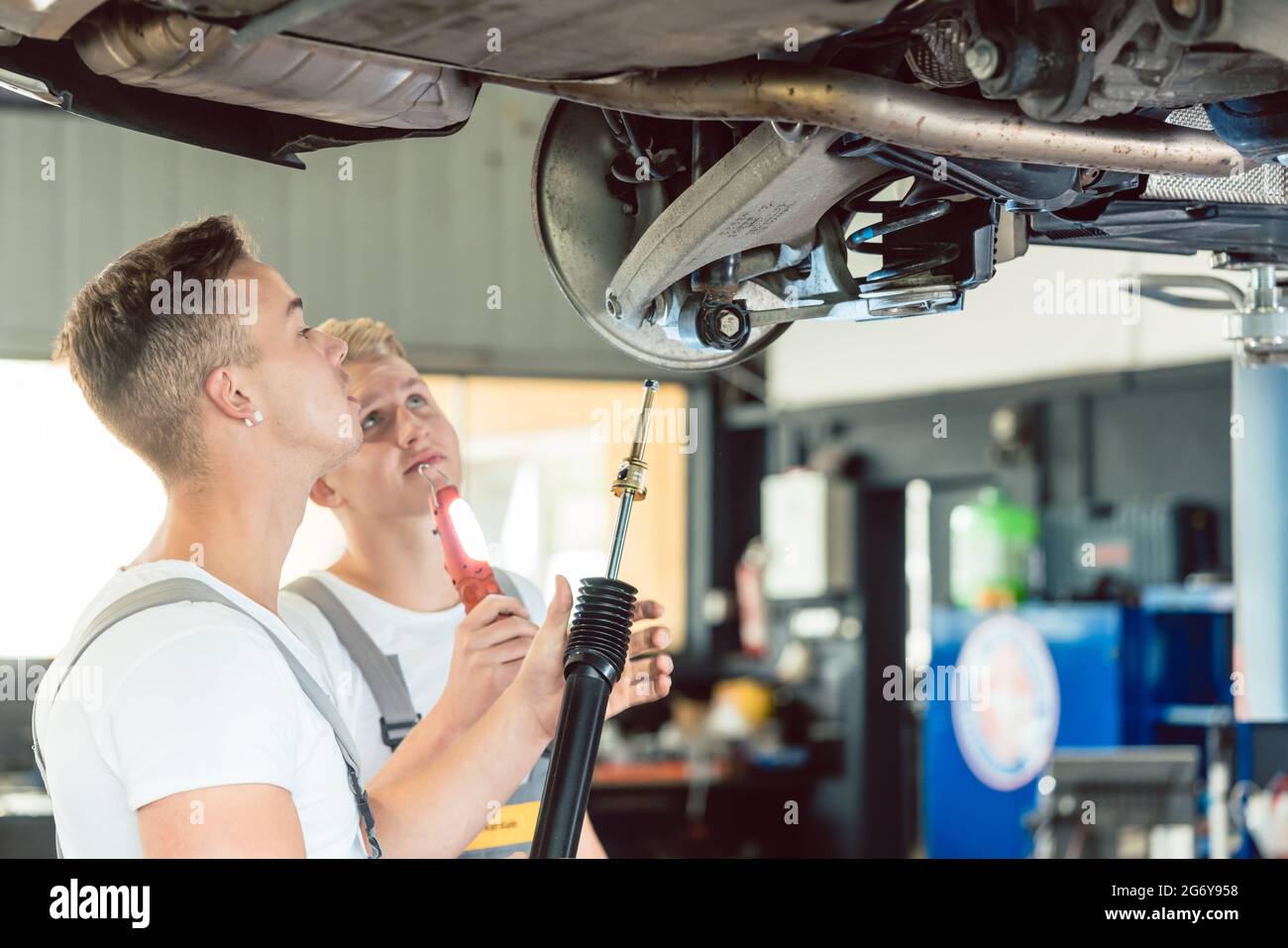 Side view of a skilled auto mechanic, replacing the shock absorbers of ...