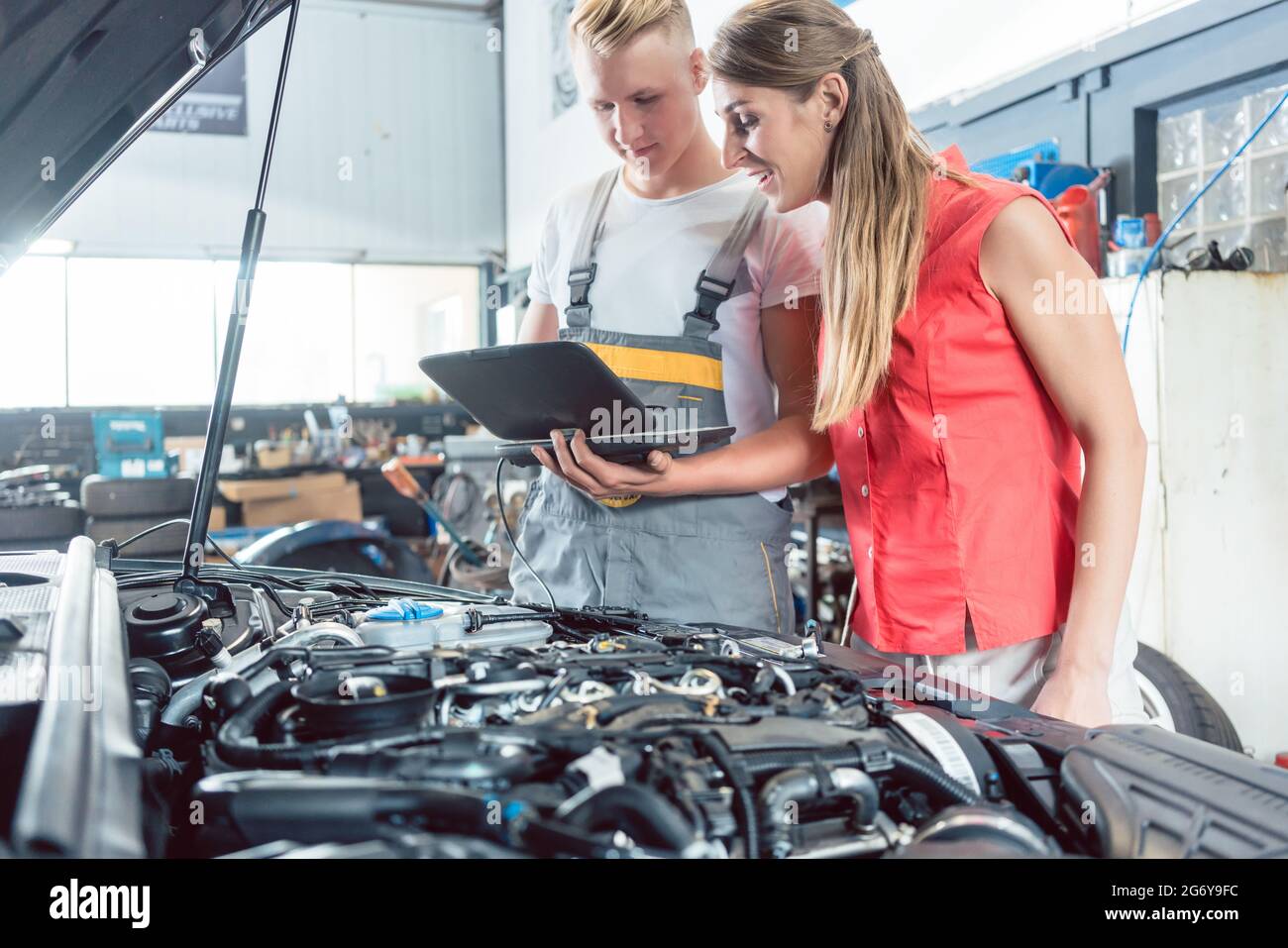 Reliable auto mechanic showing to a female customer the engine error ...