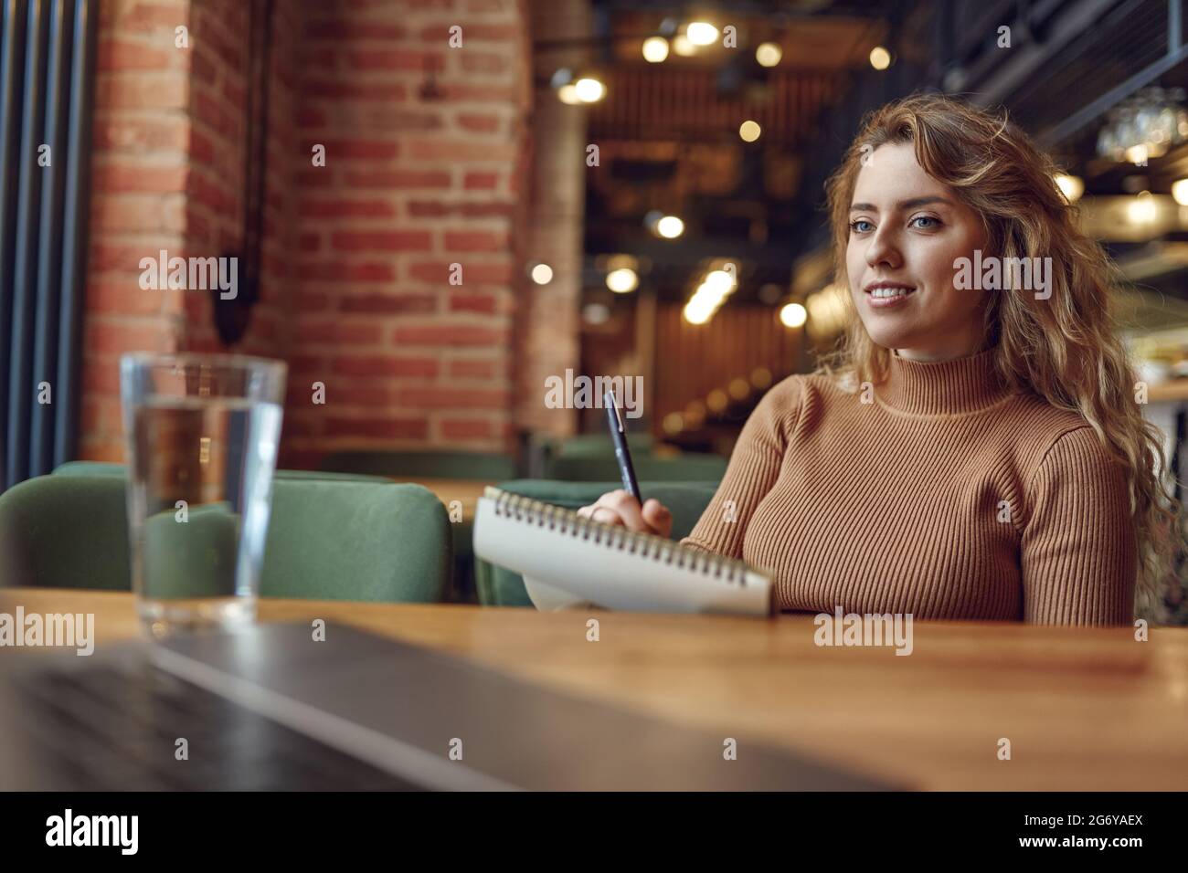 Student looking at computer screen and taking notes Stock Photo - Alamy