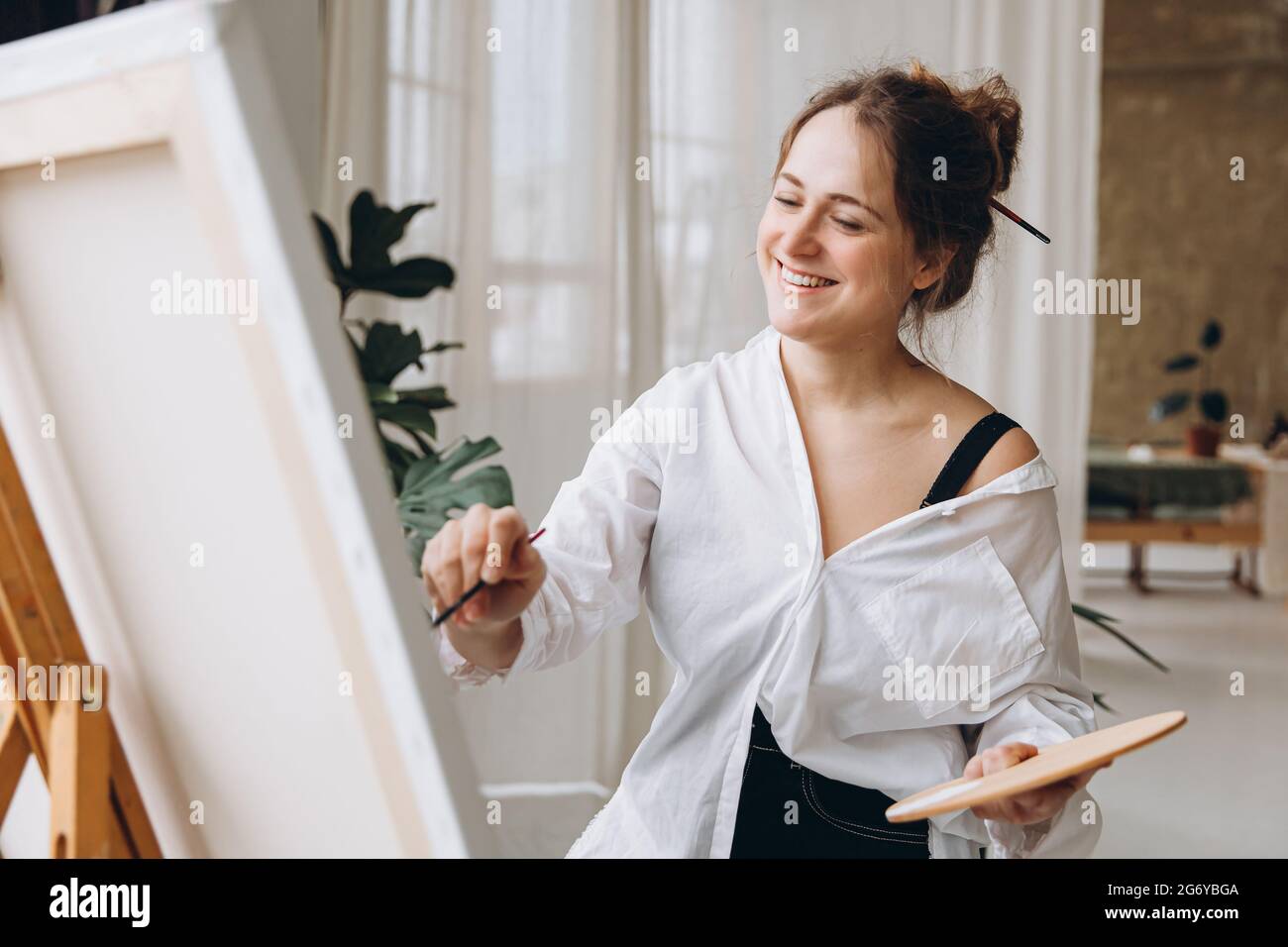 Artist painting on easel with brush and color palette Stock Photo - Alamy