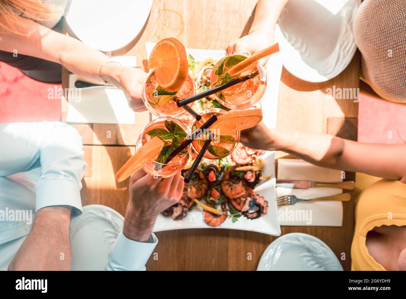 High-angle view of the hands of four young friends toasting with fresh ...