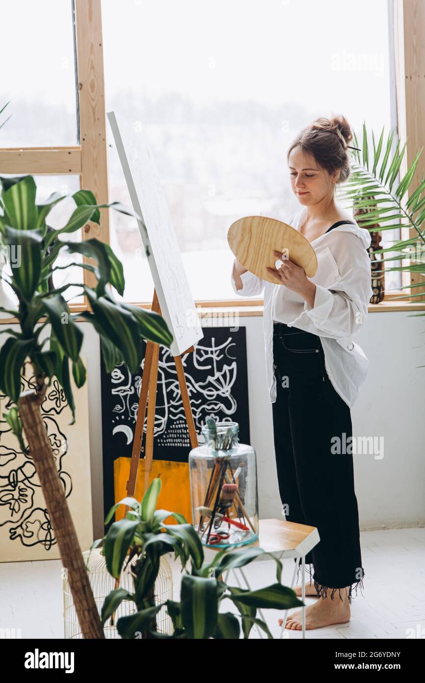 Woman standing with barefoot in studio and painting on easel Stock ...