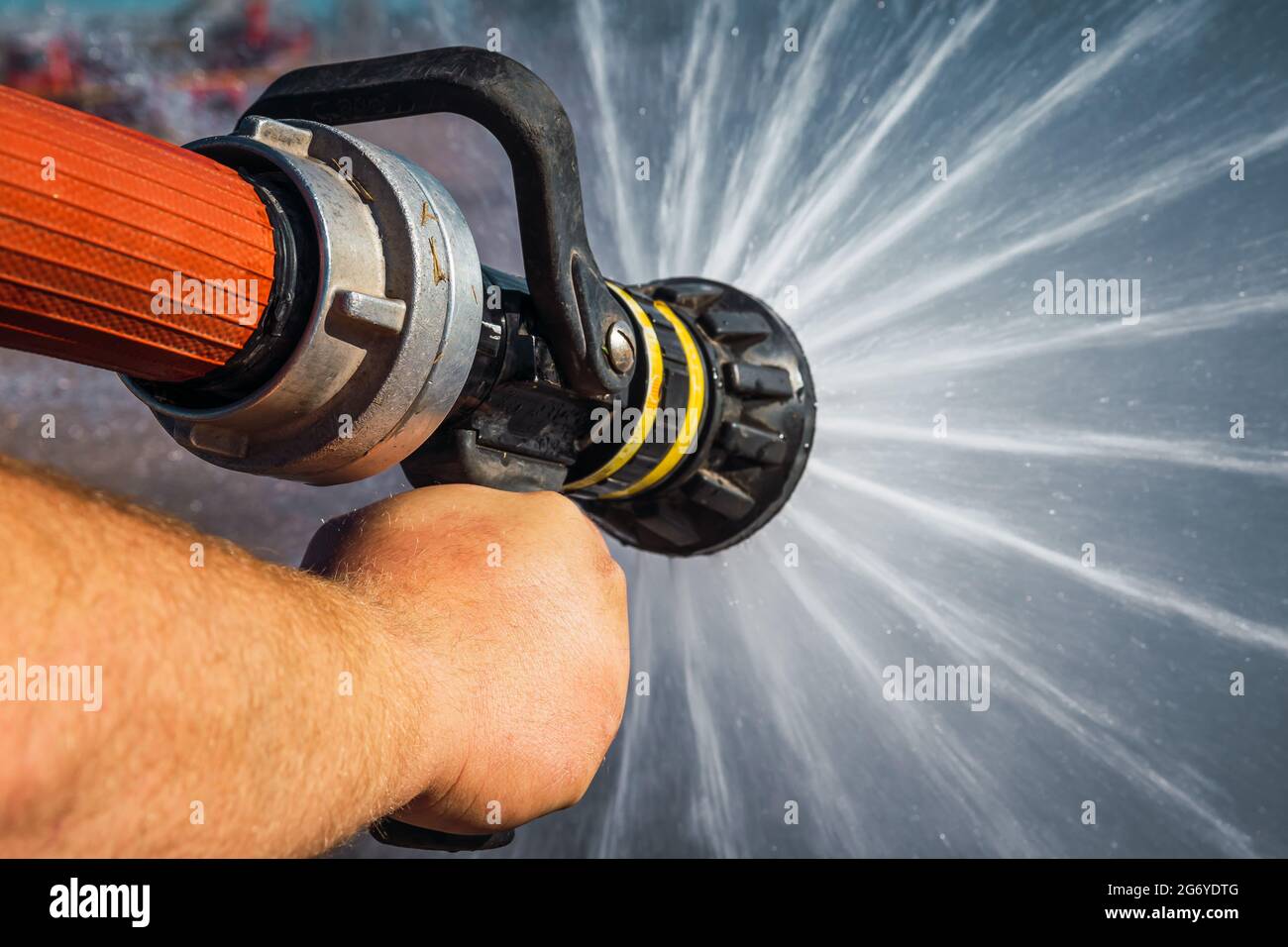 Closeup of a firefighter's hand holding a lance and splashing ...
