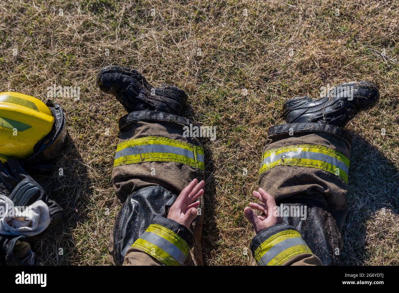 Legs of tired and wet firefighters resting on the ground outside after ...