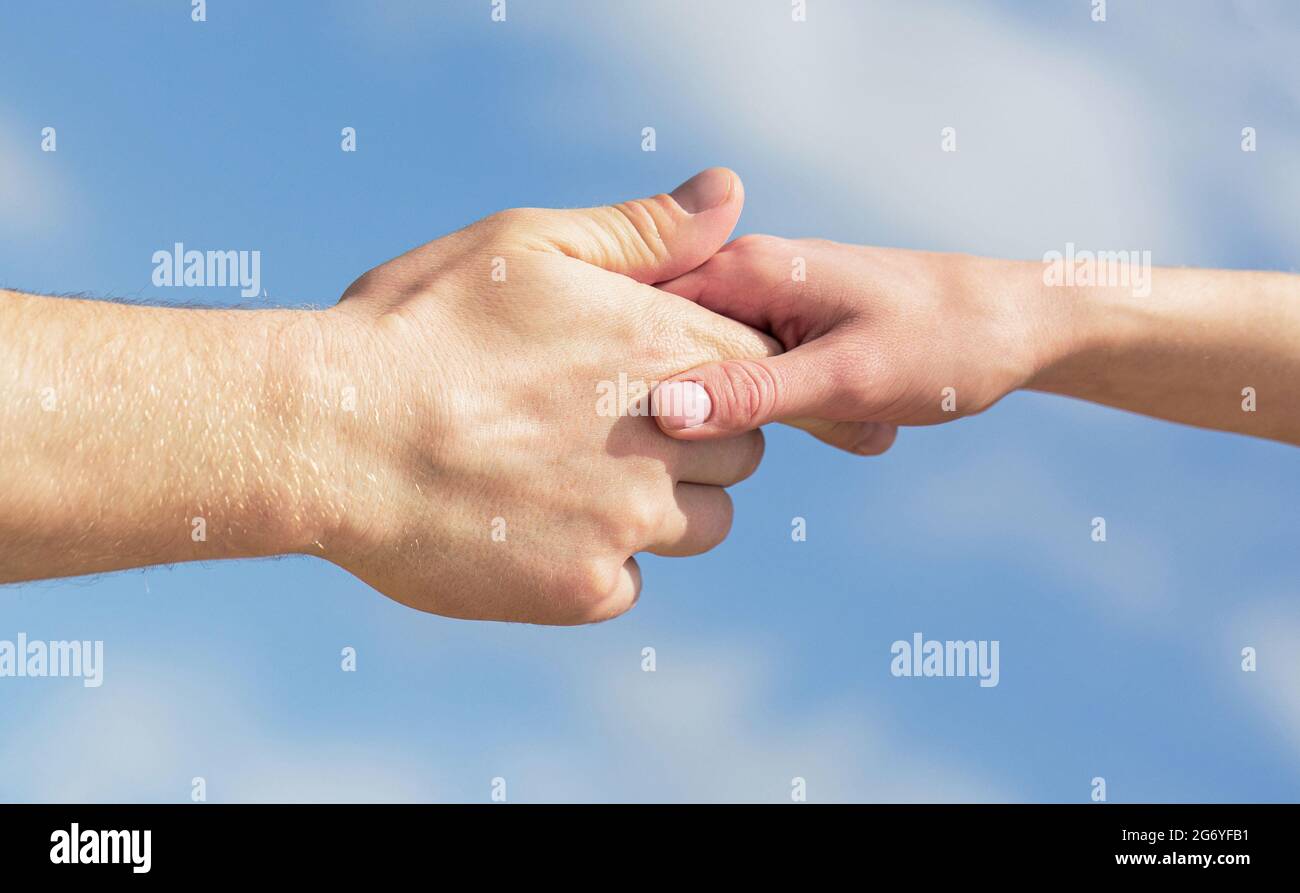 Giving a helping hand. Hands of man and woman on blue sky background ...