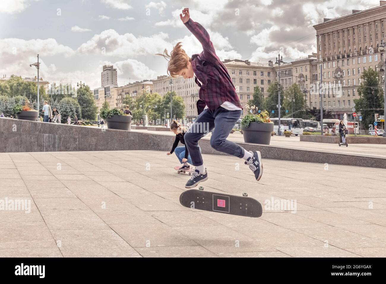 A teenage boy rides a skateboard on the square. Performing stunts ...