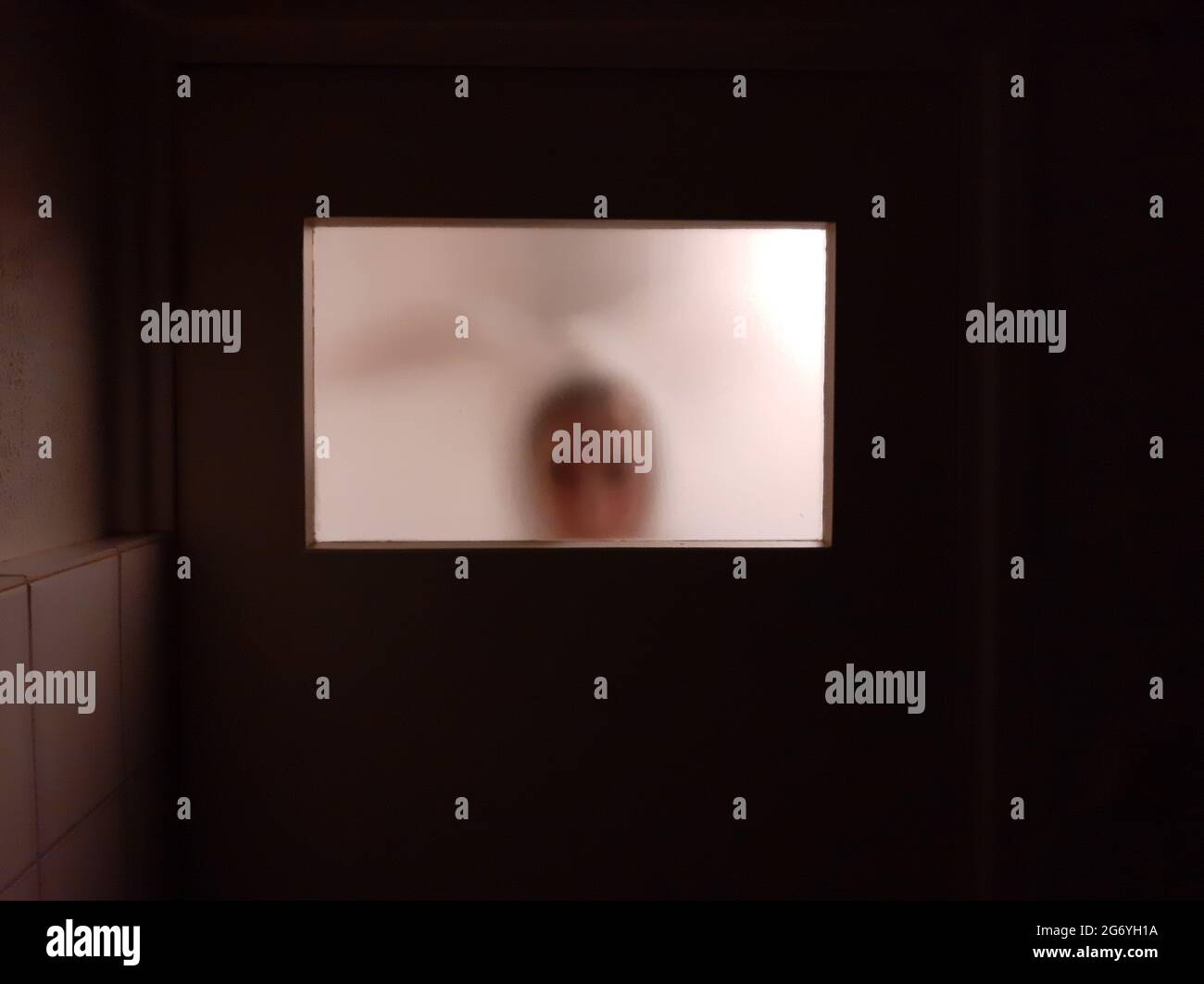 Creepy kid with bunny ears looking through satin glass window Stock ...