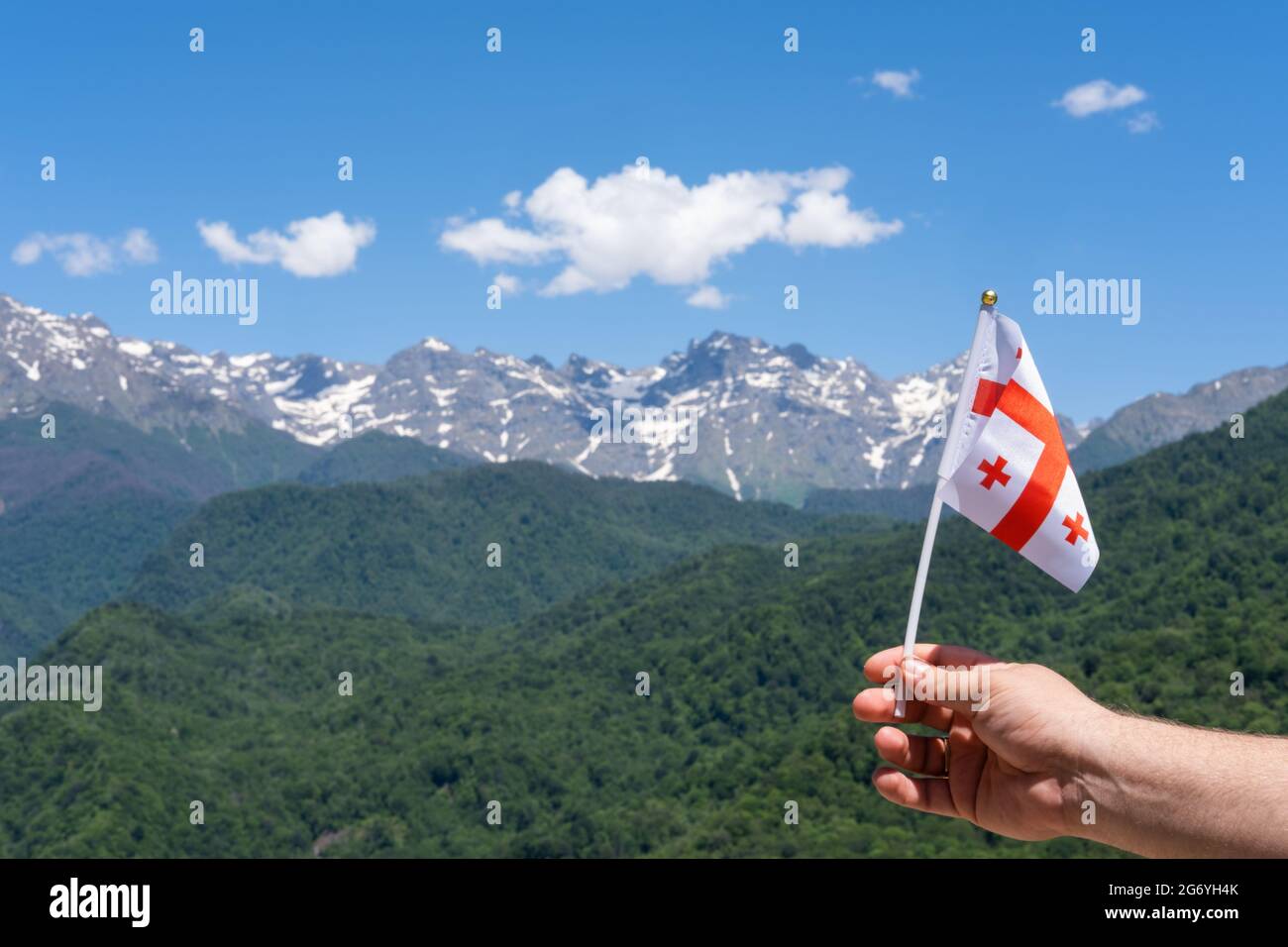 Georgian flag in man's hand on Background of Mountains and Blue Sky ...
