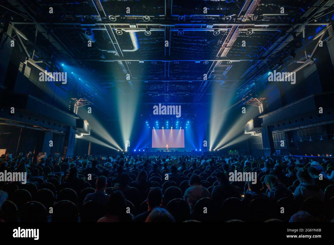 Audience sitting in front of stage with screen Stock Photo - Alamy