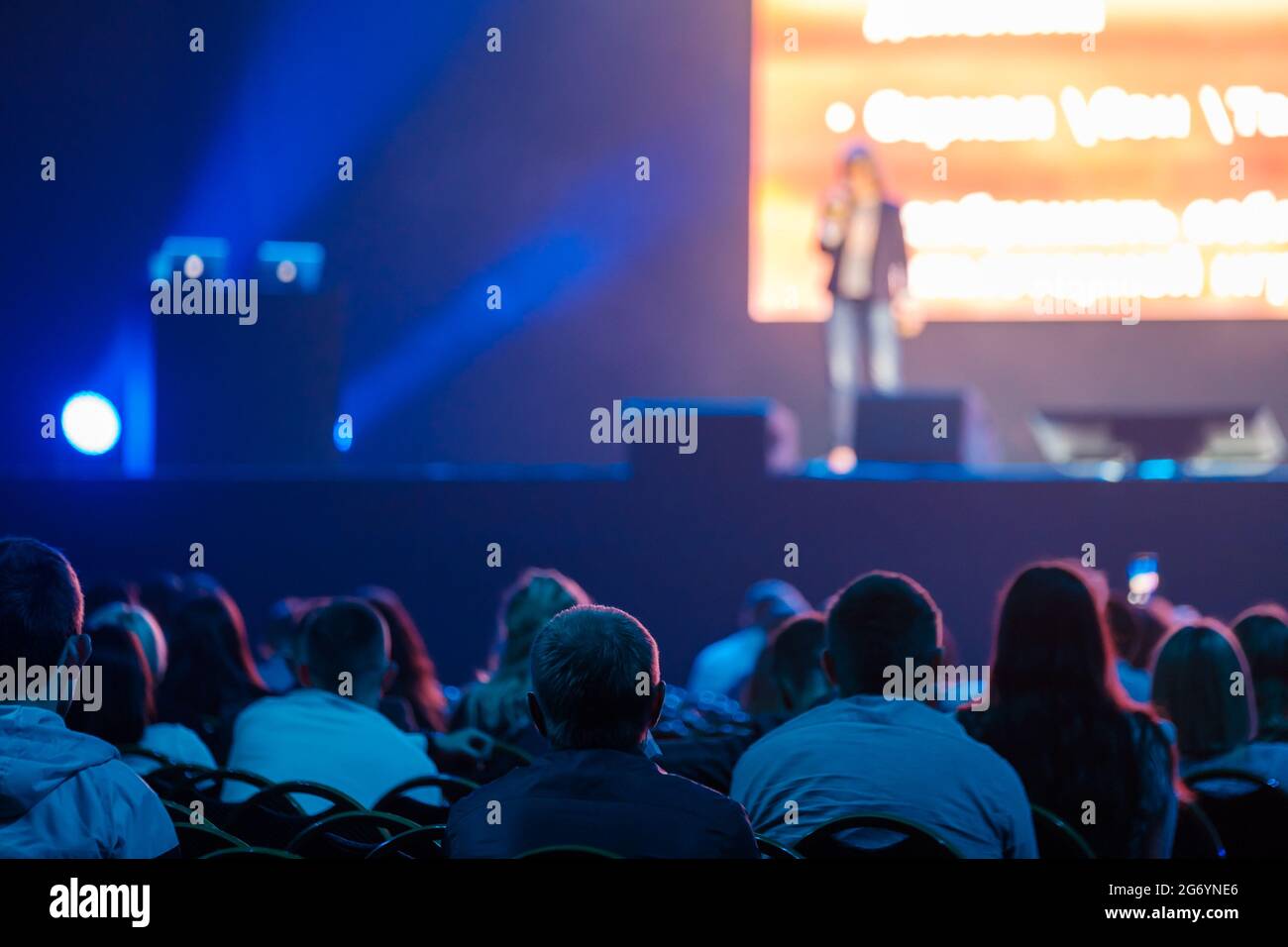 Audience listening to speaker in neon light Stock Photo - Alamy