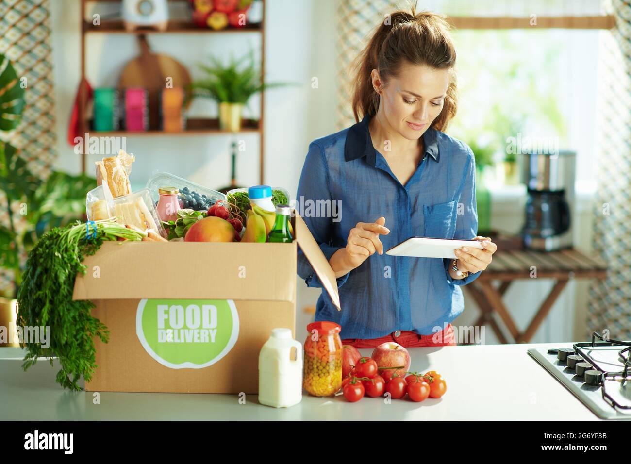 Food delivery. young female with food box using tablet PC recipes app ...