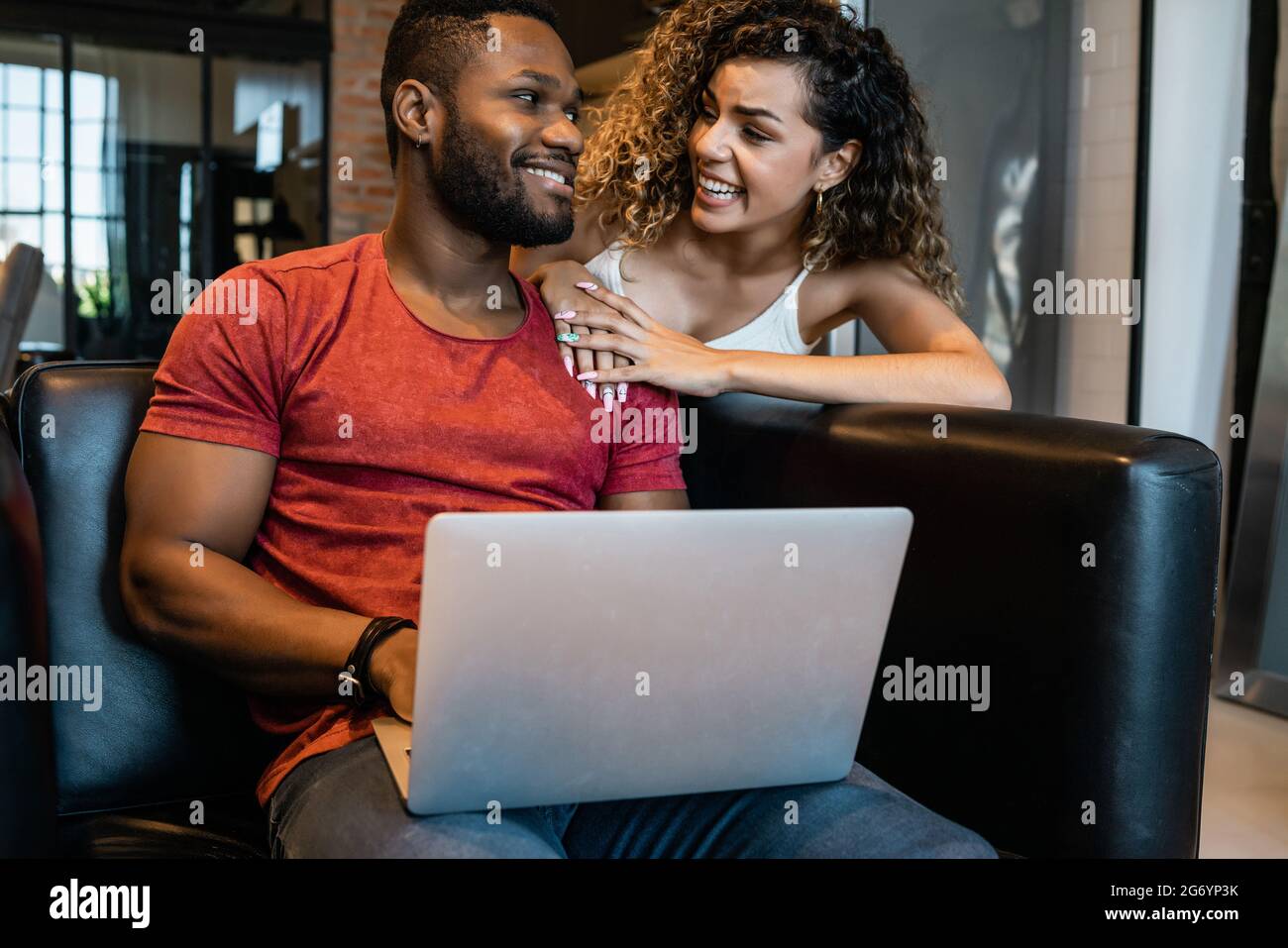 Couple using a laptop while sitting on a couch at home Stock Photo - Alamy