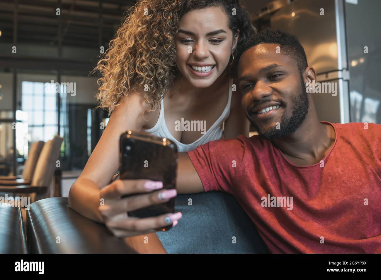 Young couple using a mobile phone at home Stock Photo - Alamy
