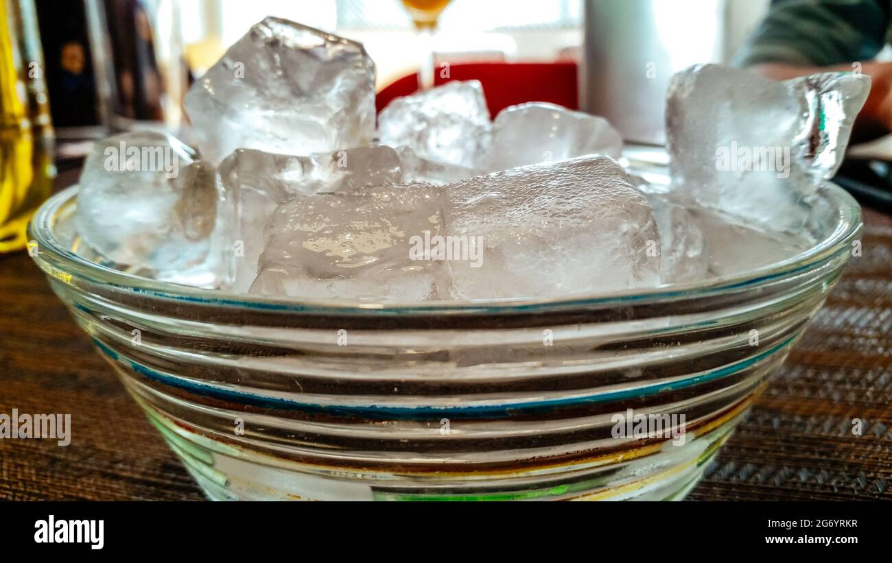 A glass container with ice cubes on a table Stock Photo - Alamy
