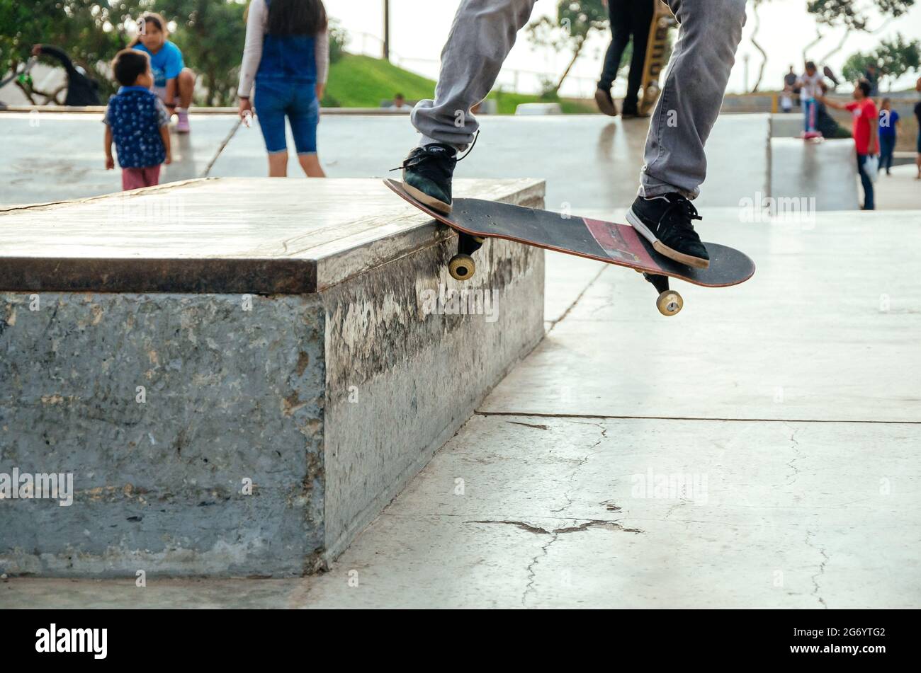 Skateboarder is doing a crooked grind trick on a bench in skatepark ...