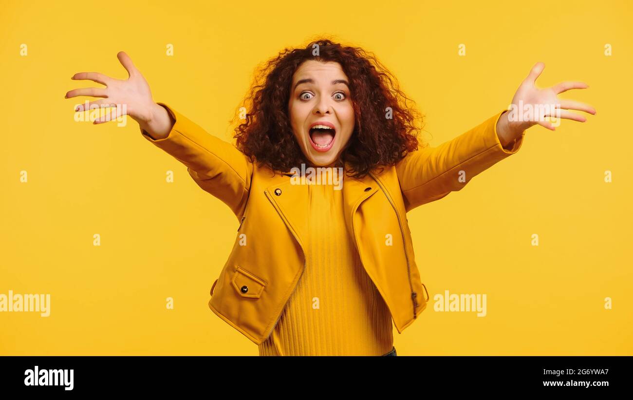 excited young woman with outstretched hands isolated on yellow Stock ...