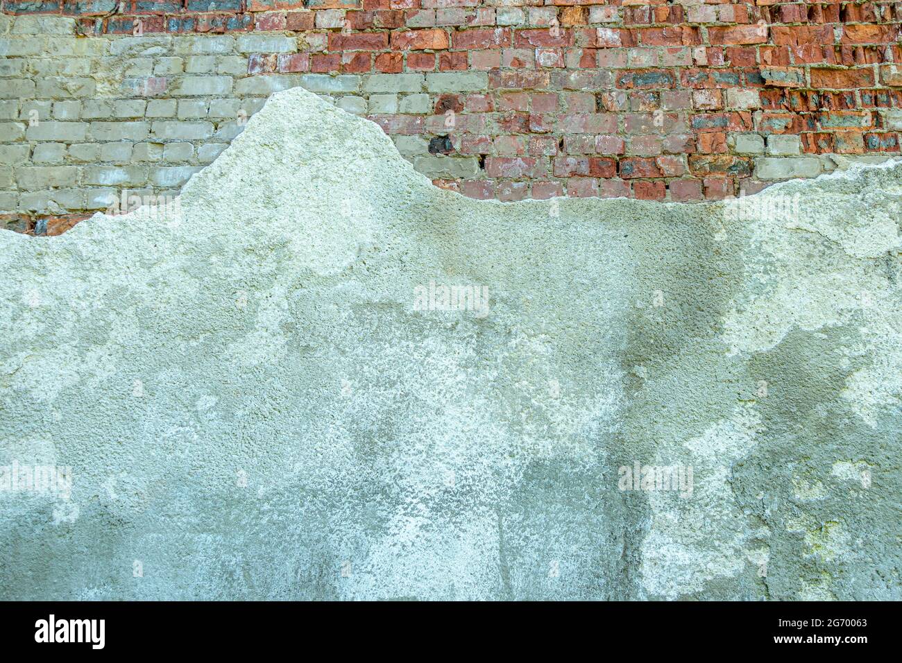 Gray plastered old brickwall with chipped stucco pieces. Grunge red and ...
