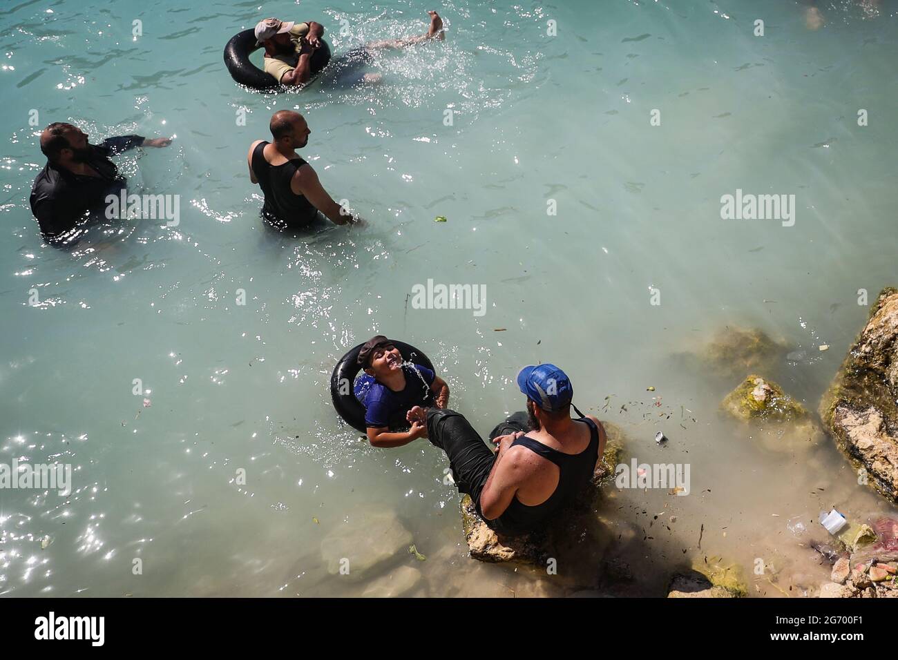 Darkush, Syria. 09th July, 2021. Syrians swim in the water of Asi ...
