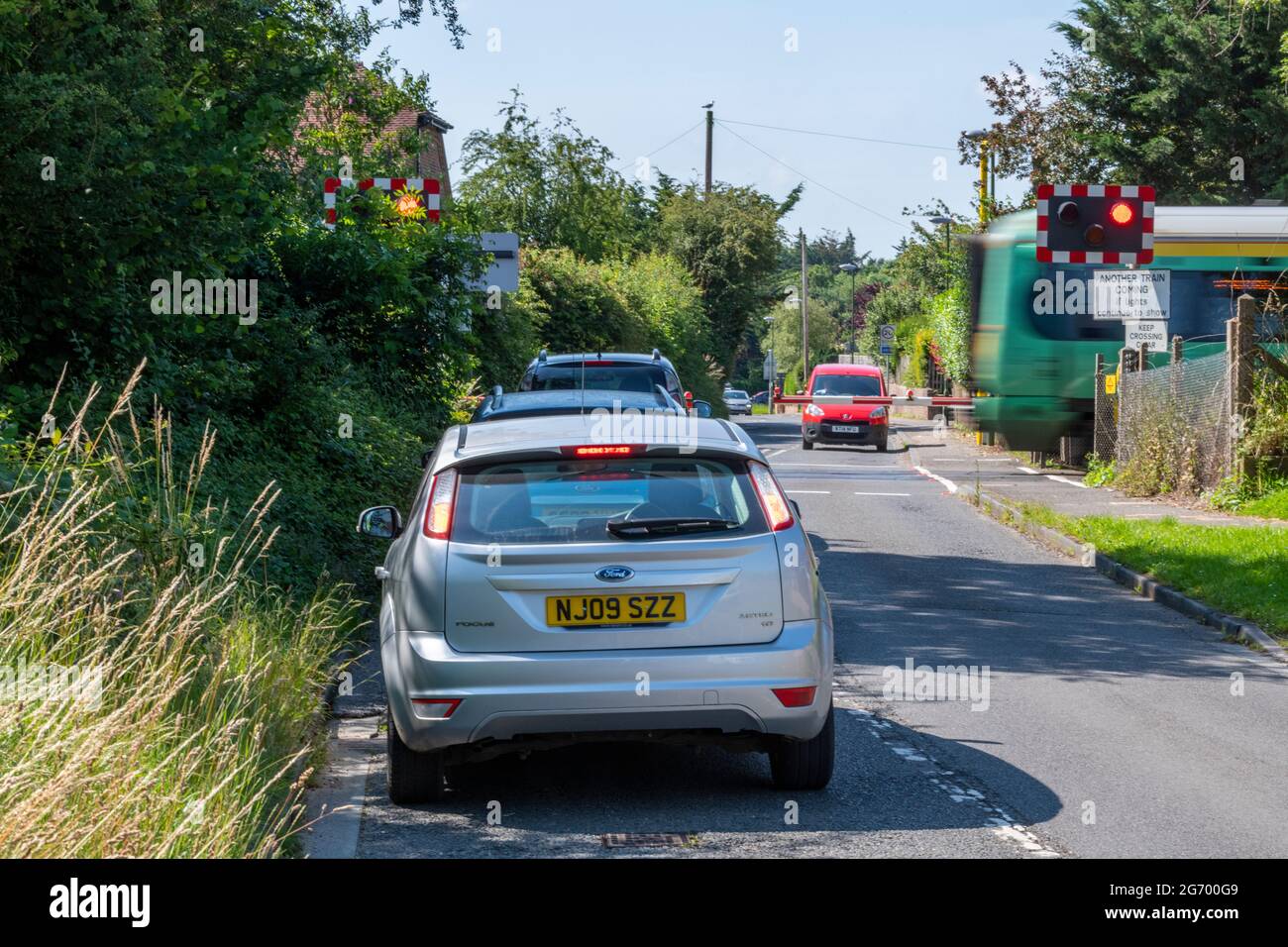 cars waiting a a level crossing automatic half barriers on the railway lines an tracks in west ...