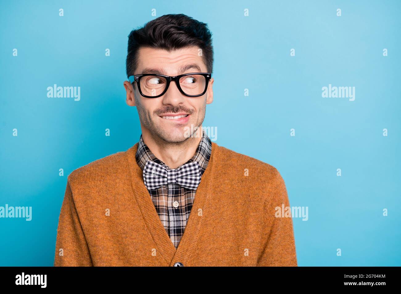 Photo of satisfied young guy biting lips look empty space thinking ...