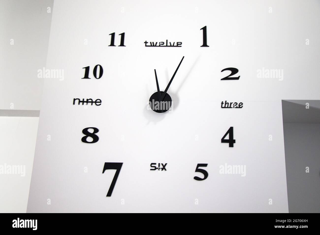Clock on the white wall with numbers and words of time Stock Photo - Alamy