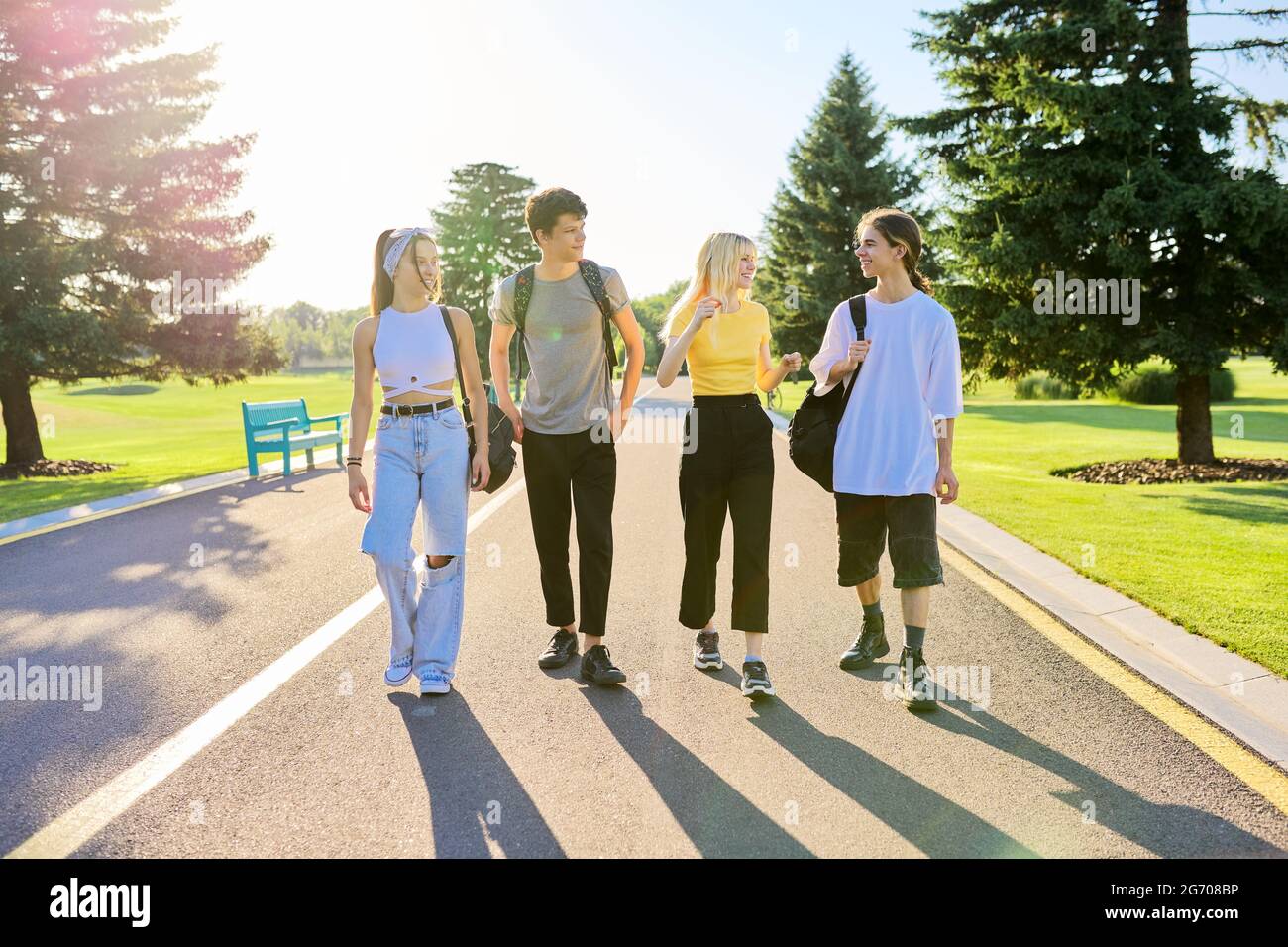 Outdoor, four teenagers walking together on road Stock Photo - Alamy