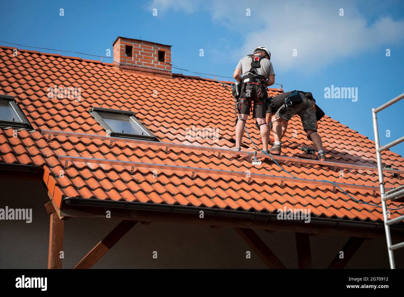Two engineers on the house roof making construction under photovoltaic ...