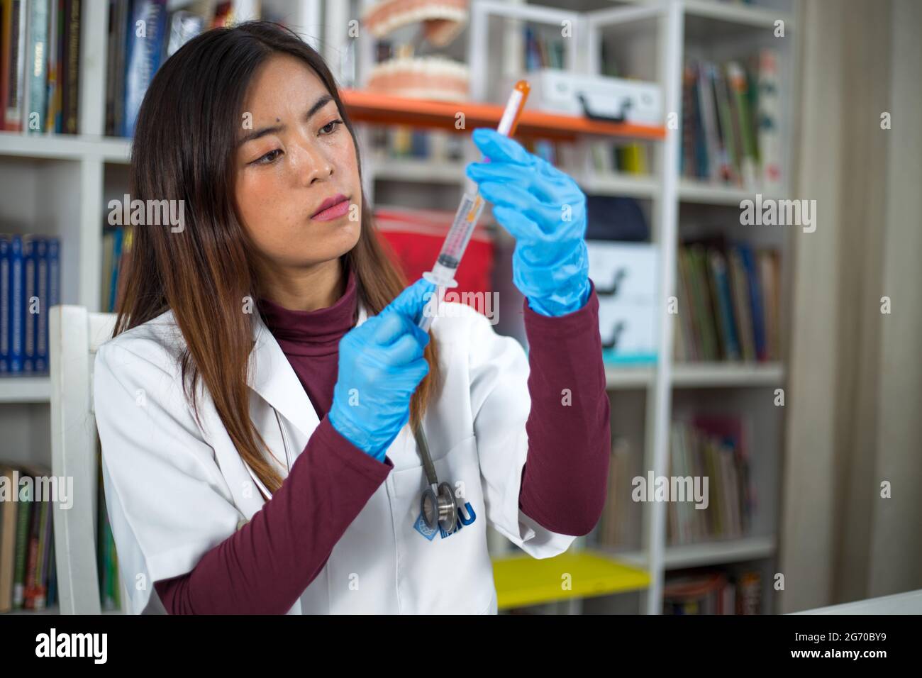 Young southeast asian female doctor filling a syringe with the blood ...