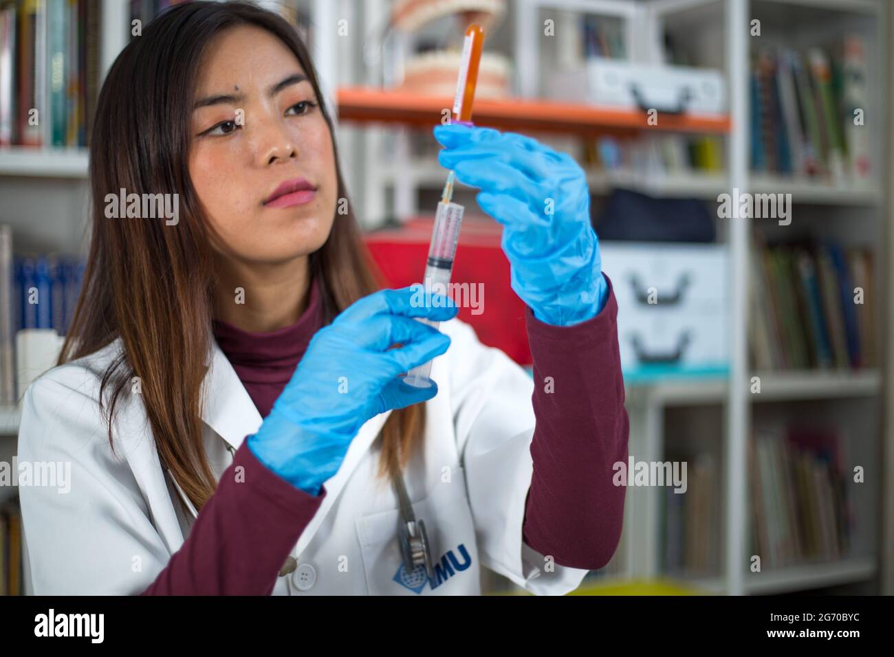Young southeast asian female doctor filling a syringe with the blood ...